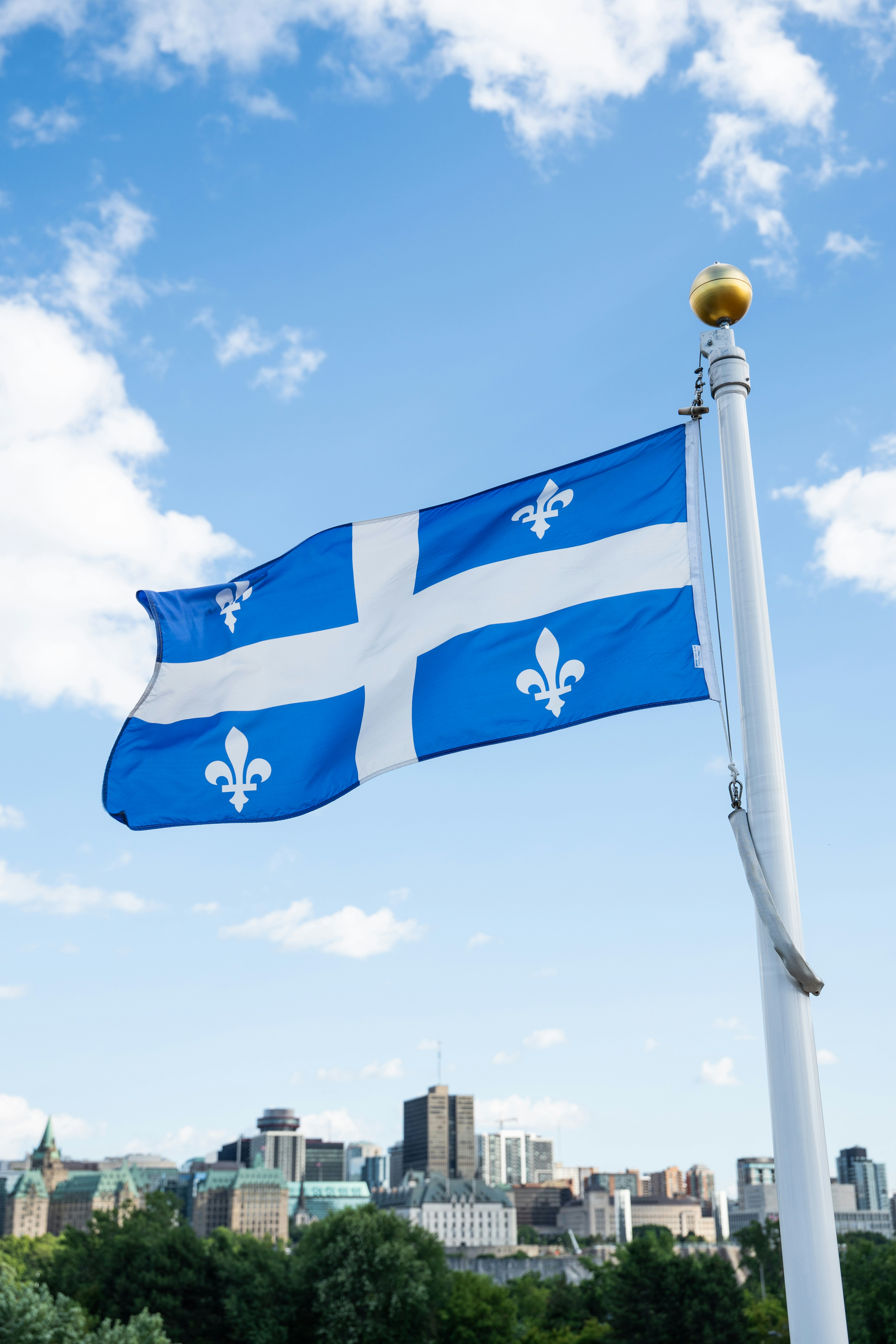 Flag of Quebec Nationhood Waving Over City Silhouette