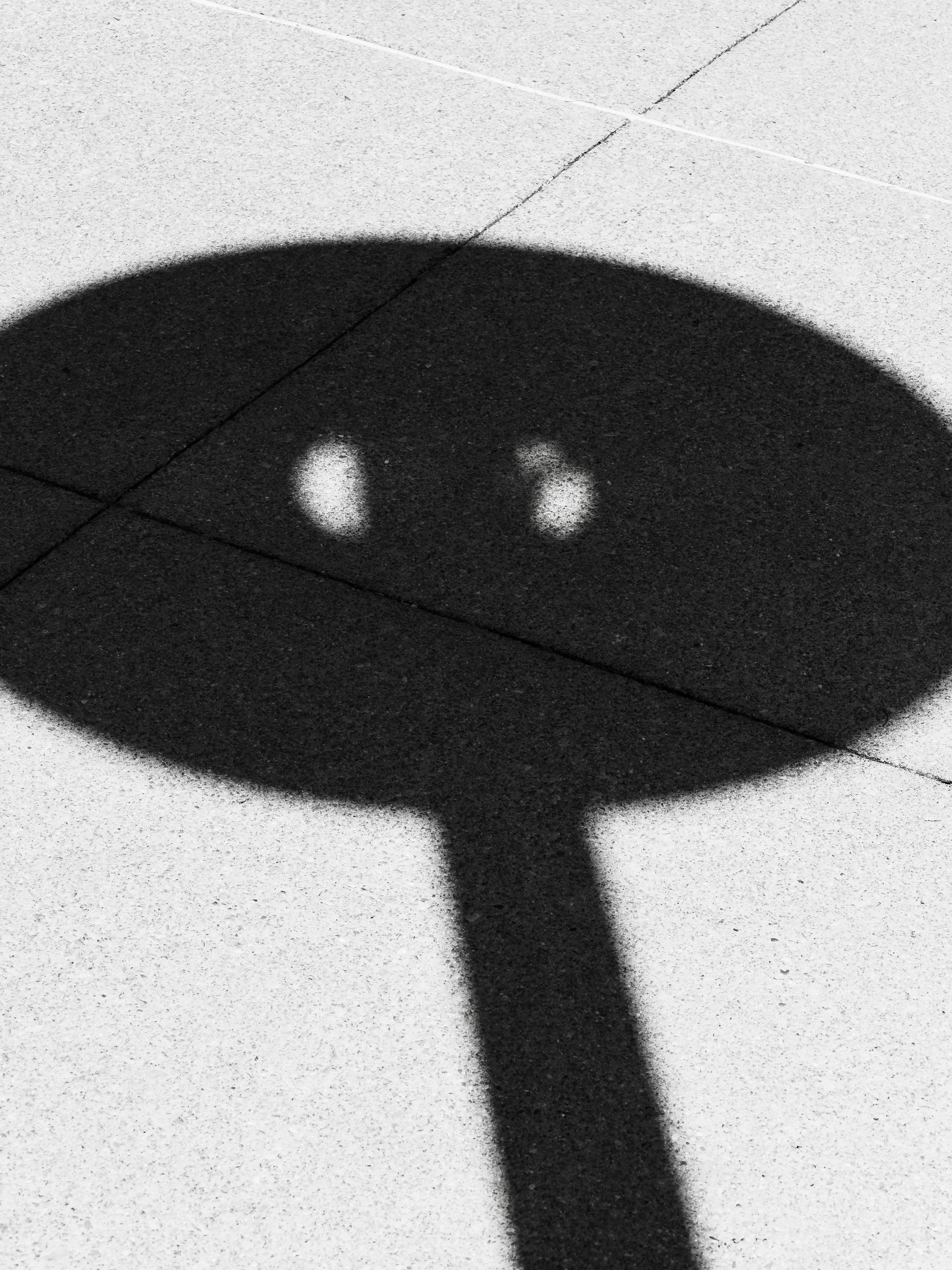 Shadowed Smile: A Playful Shadow on Flat Concrete