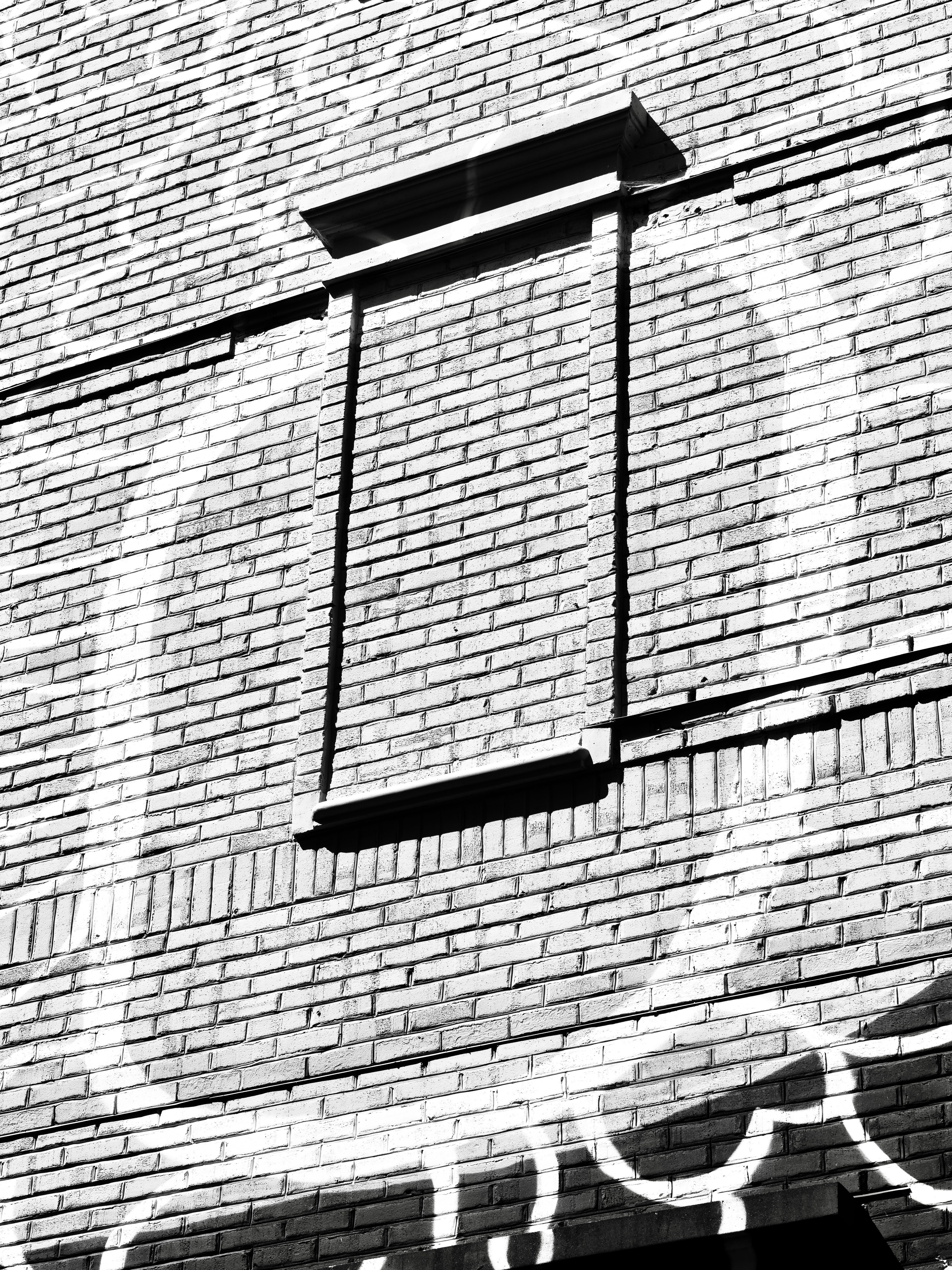 Grooved Brick Wall with Shuttered Window and Graffiti Shadow