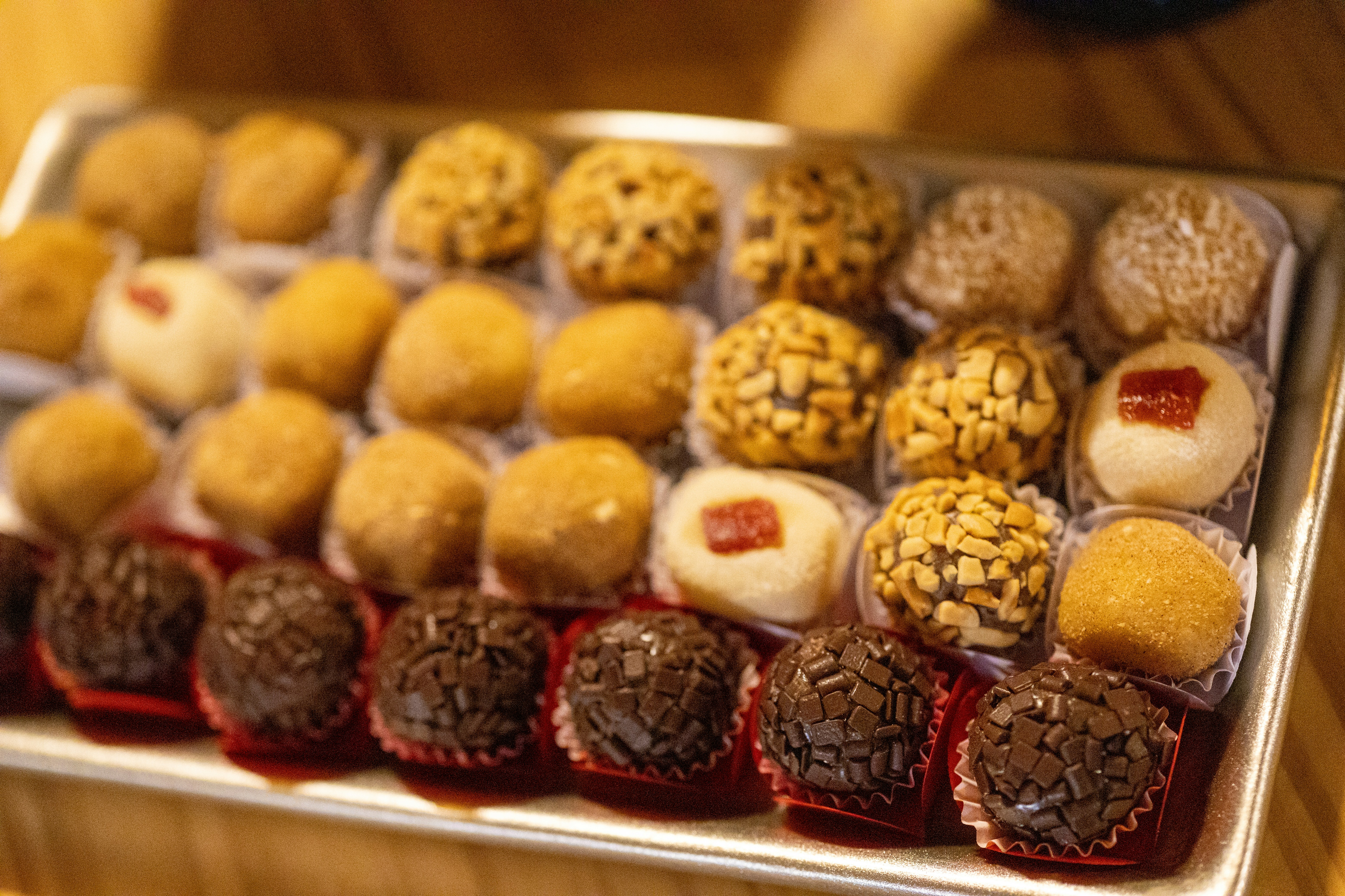 A tray of assorted brigadeiros and truffles with chocolate, nut, and fruit toppings