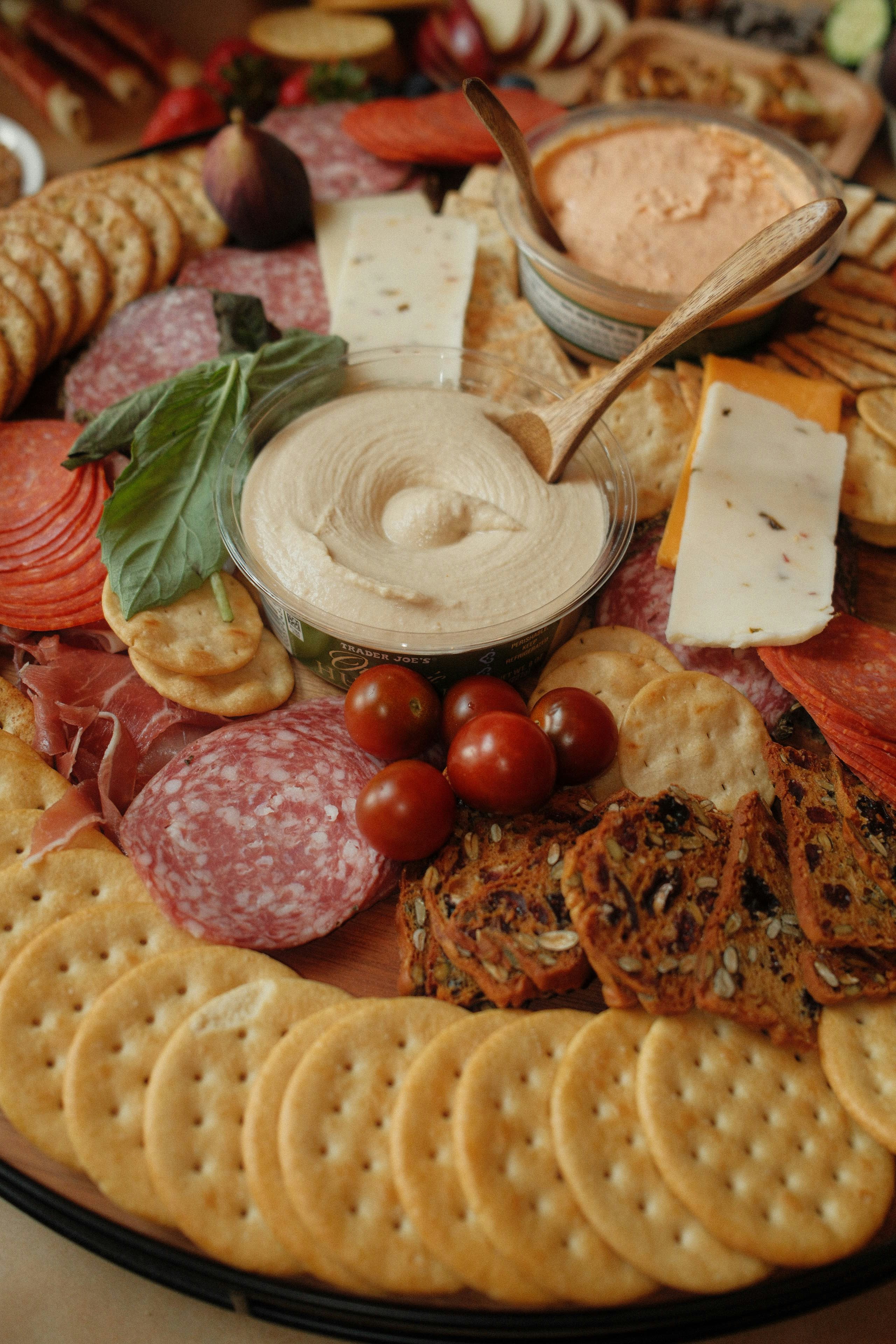 Creamy hummus centerpiece among a lavish charcuterie spread