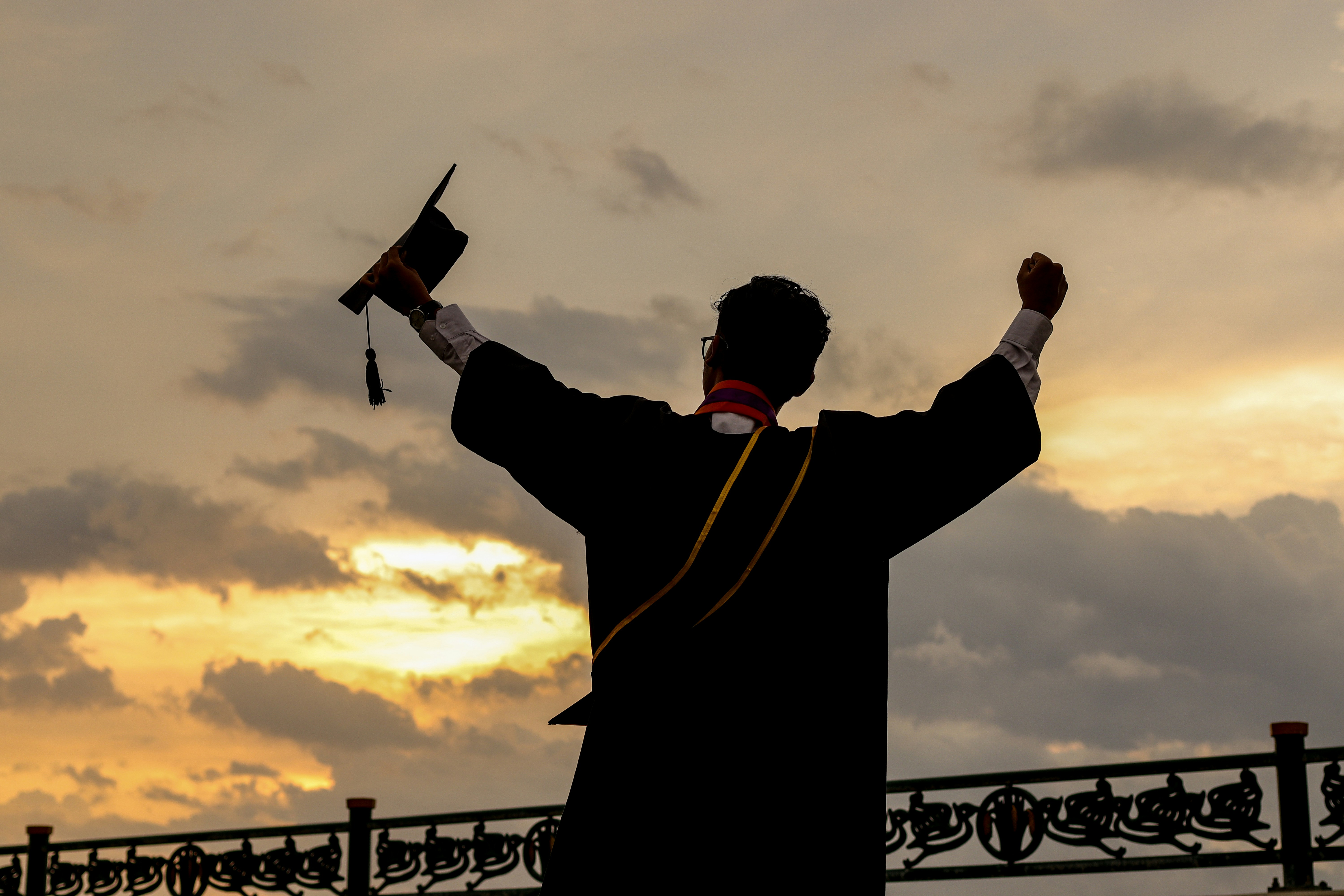 Silhouette of a Graduate Reaching for the Sunset