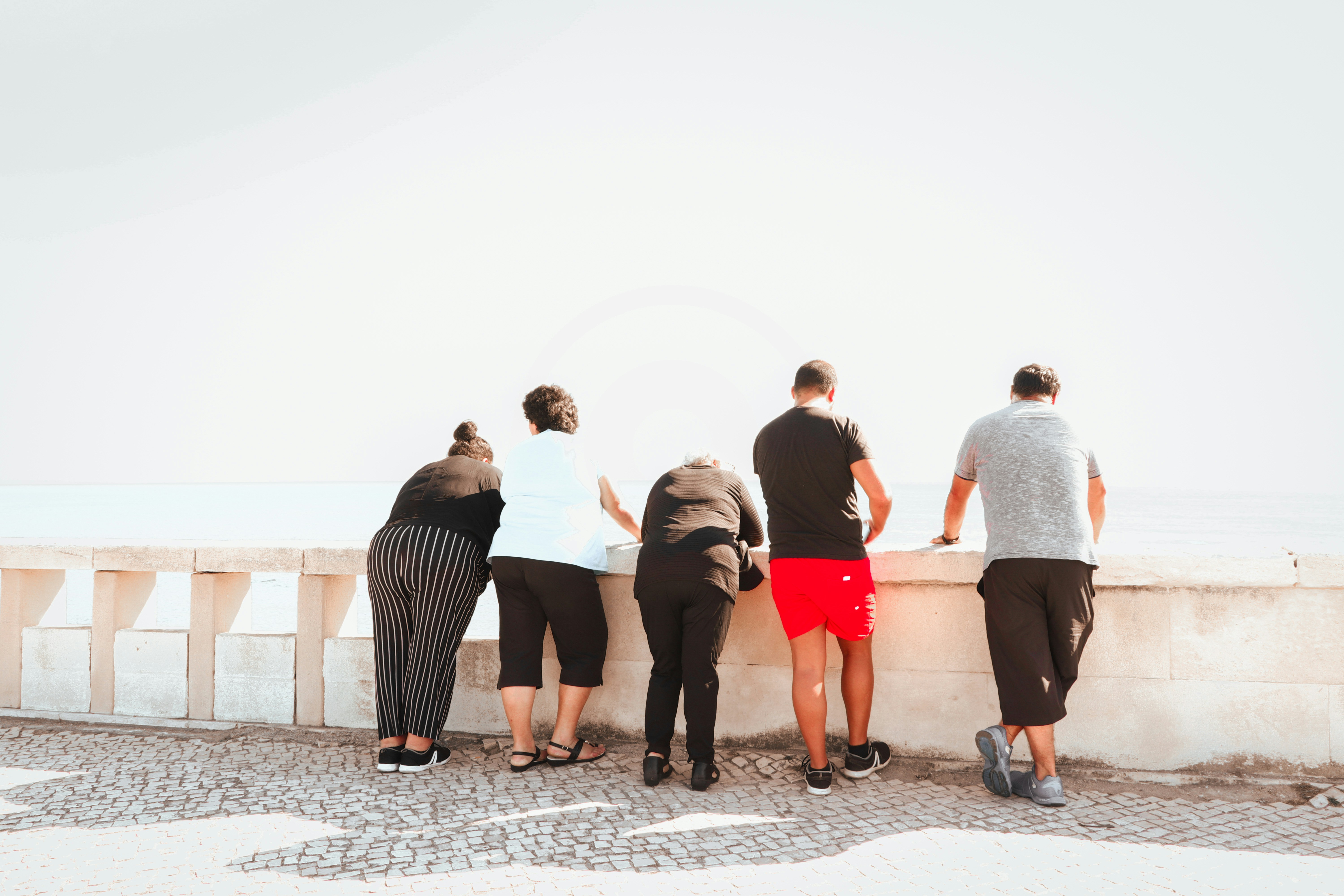 Group by the seawall: silhouettes facing the horizon on a sunlit promenade