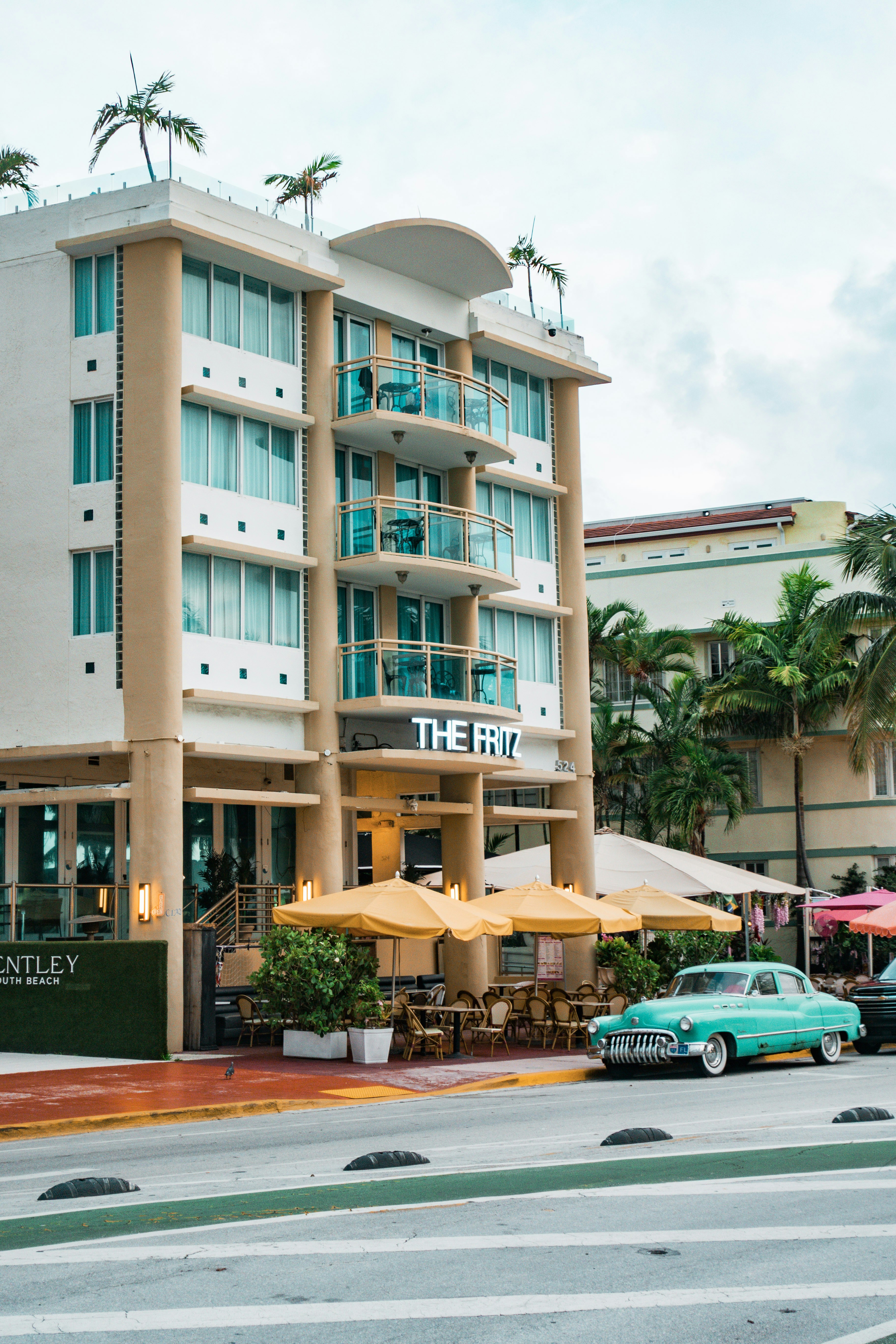 The Frilled Drive: A Coconut Coast Hotel Front with a Teal Classic on Main Street