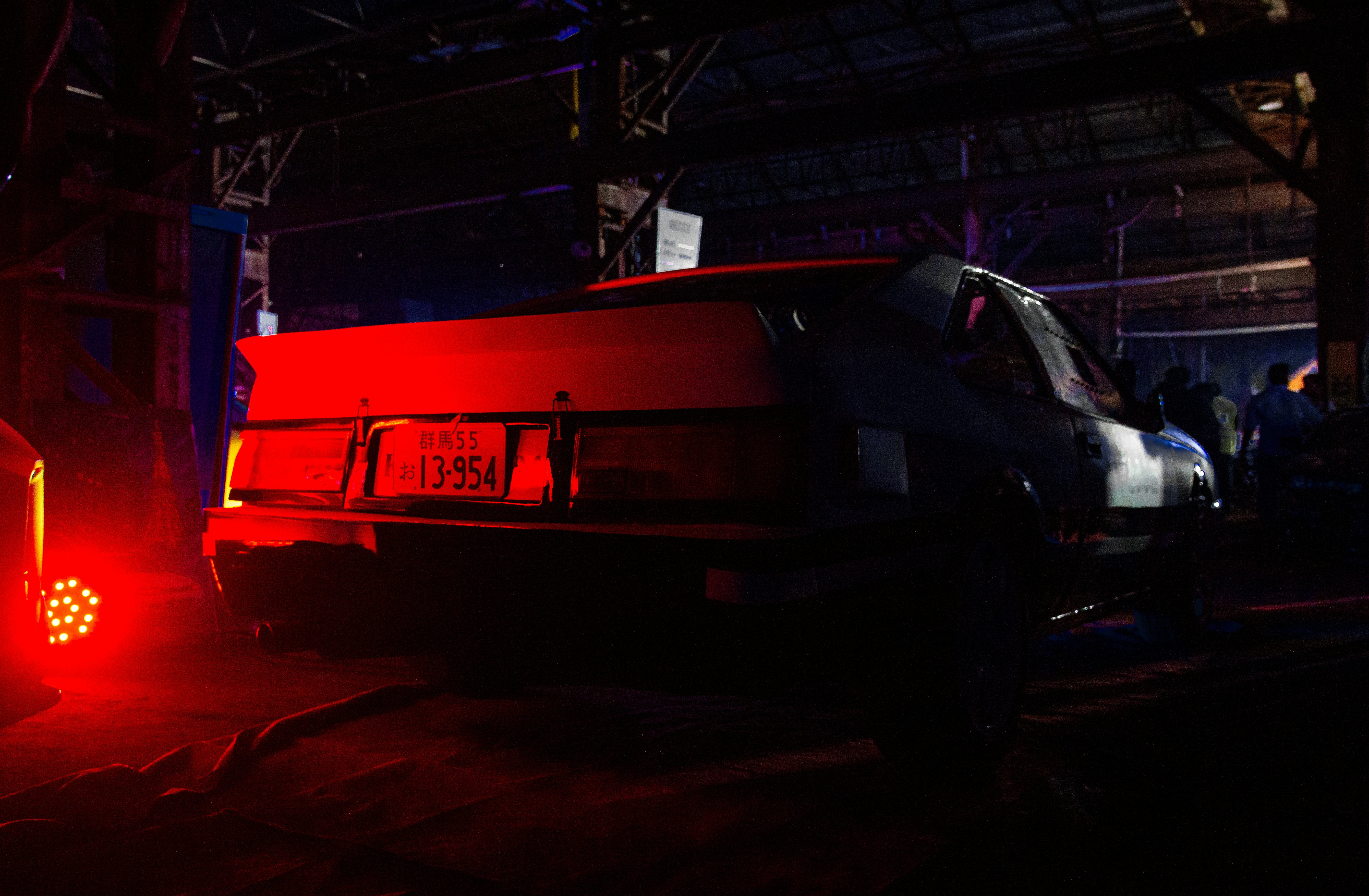 Midnight revival: a red-tailed car under dim depot lights