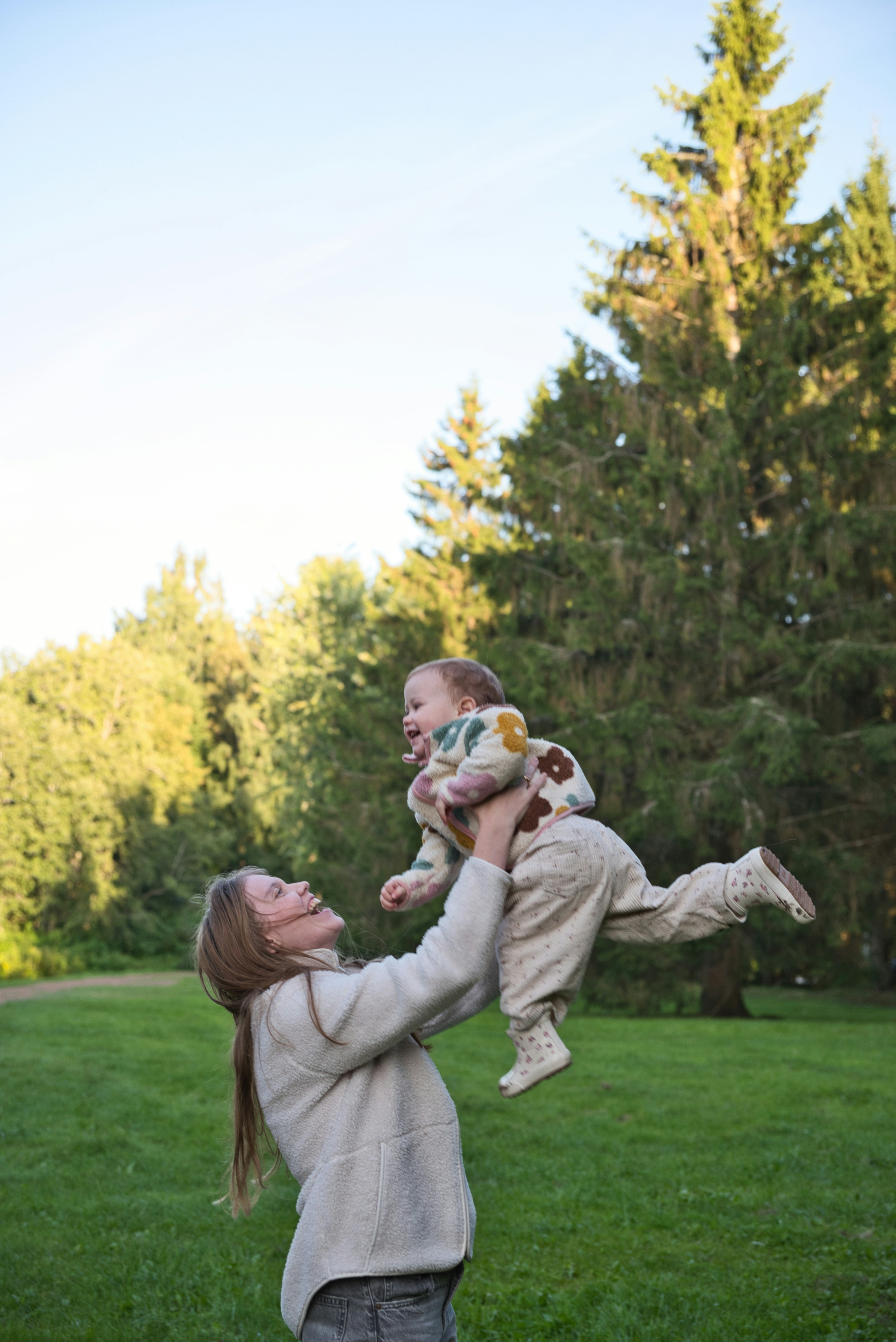 Joyful Lift: Mother and Baby in Sunlit Park