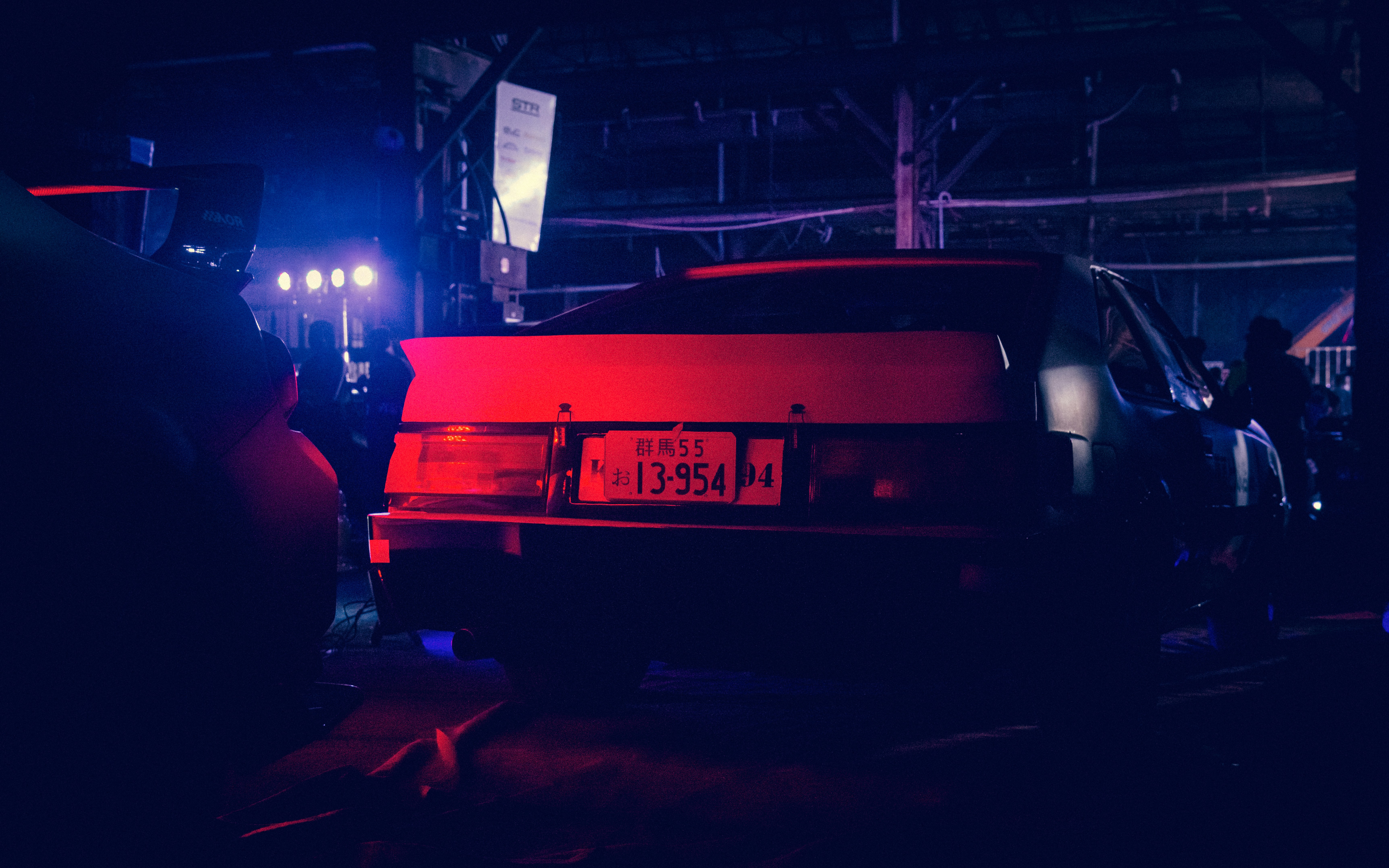 A white Toyota AE86 Corolla Levin inspired by the iconic Initial D racing car, displayed at an automotive exhibition inside the abandoned Richardson & Cruddas factory in Mumbai, India. Photographed at night with a red light flashing onto it. A special thank you to Khalid for letting me photograph his car (instagram.com/khalid.jdm).