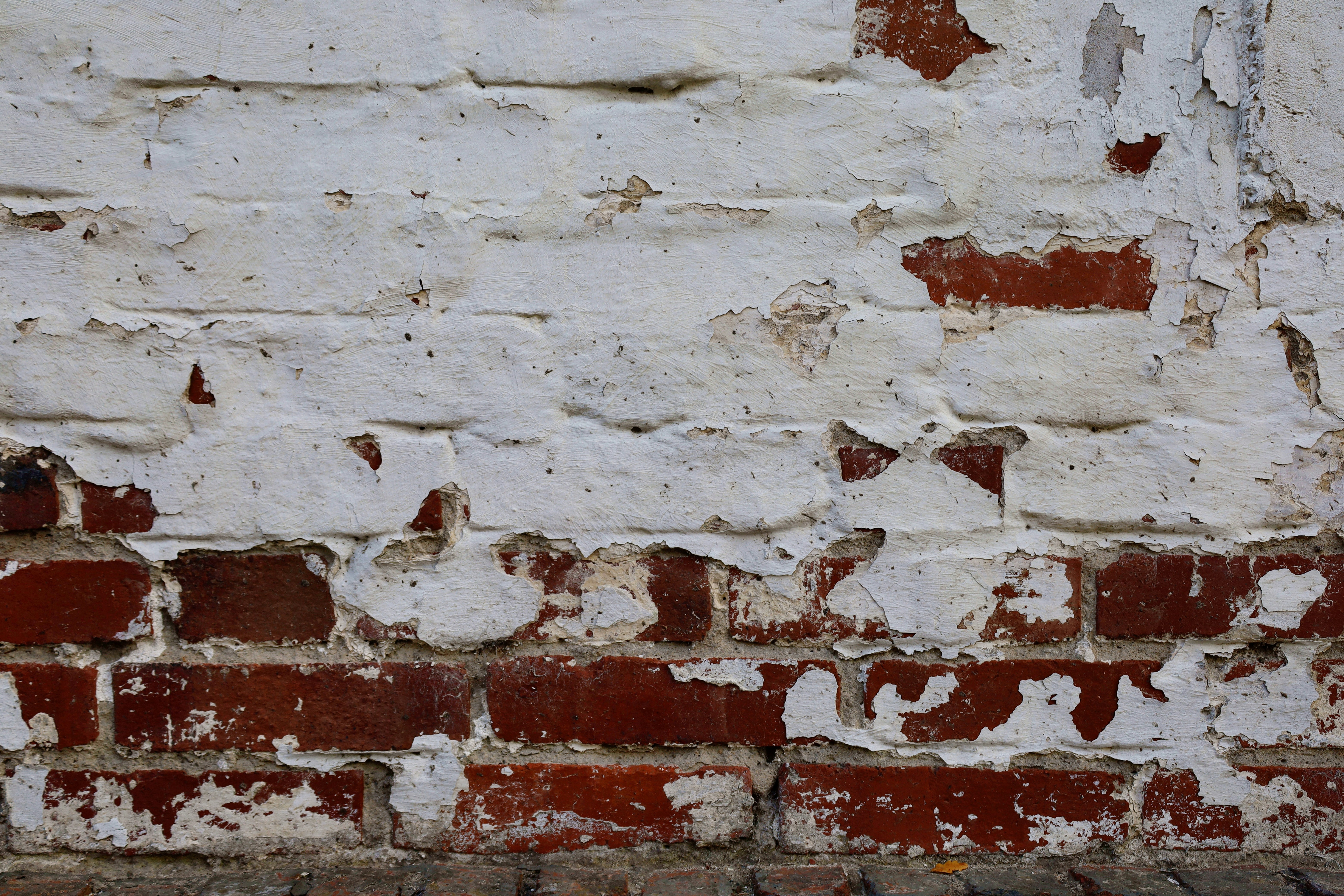 Weathered Brick Wall: Layers of Red and White Peeling Paint