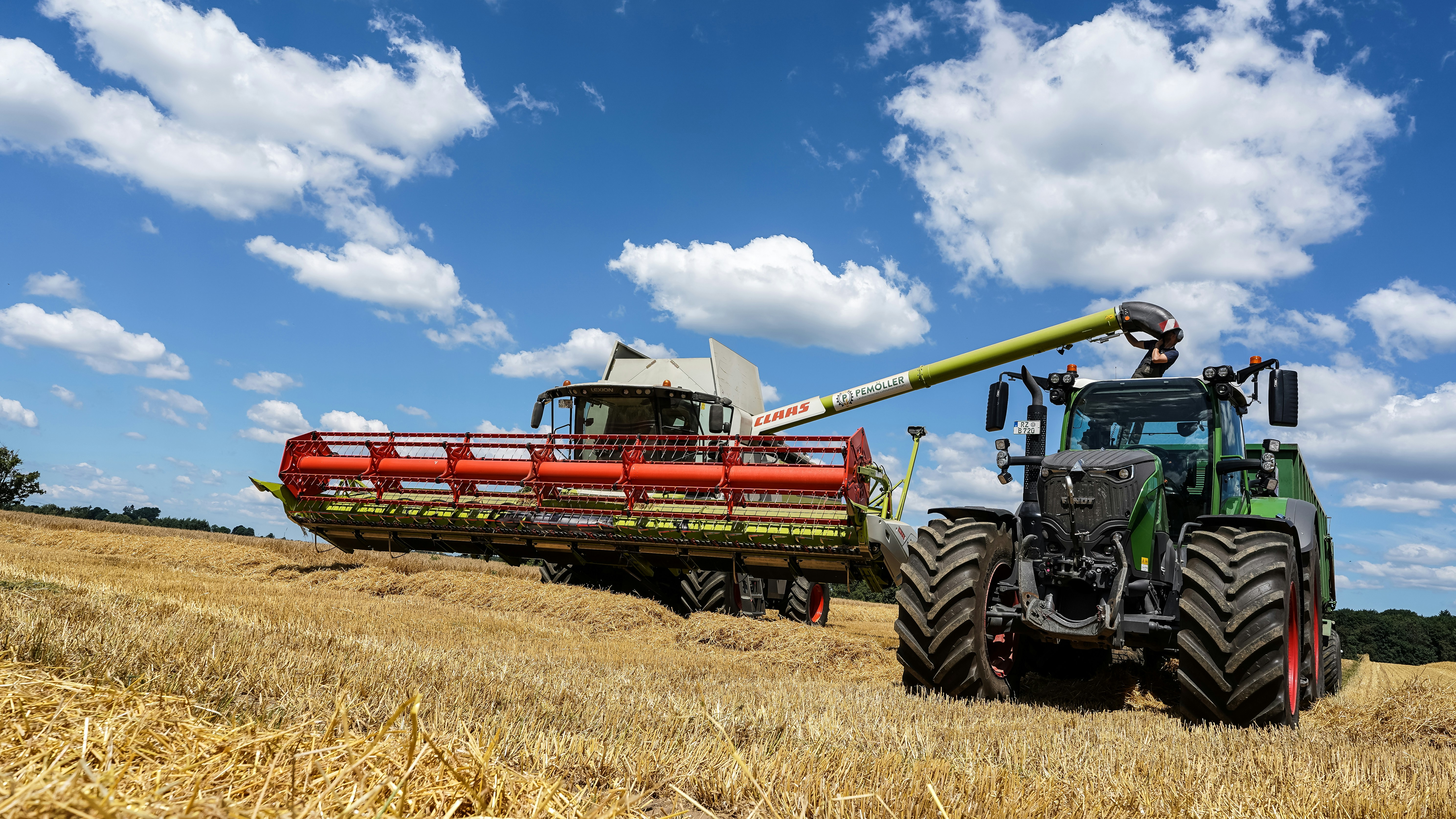 Harvest Streak: Green Tractor at Full Reach in a Golden Field