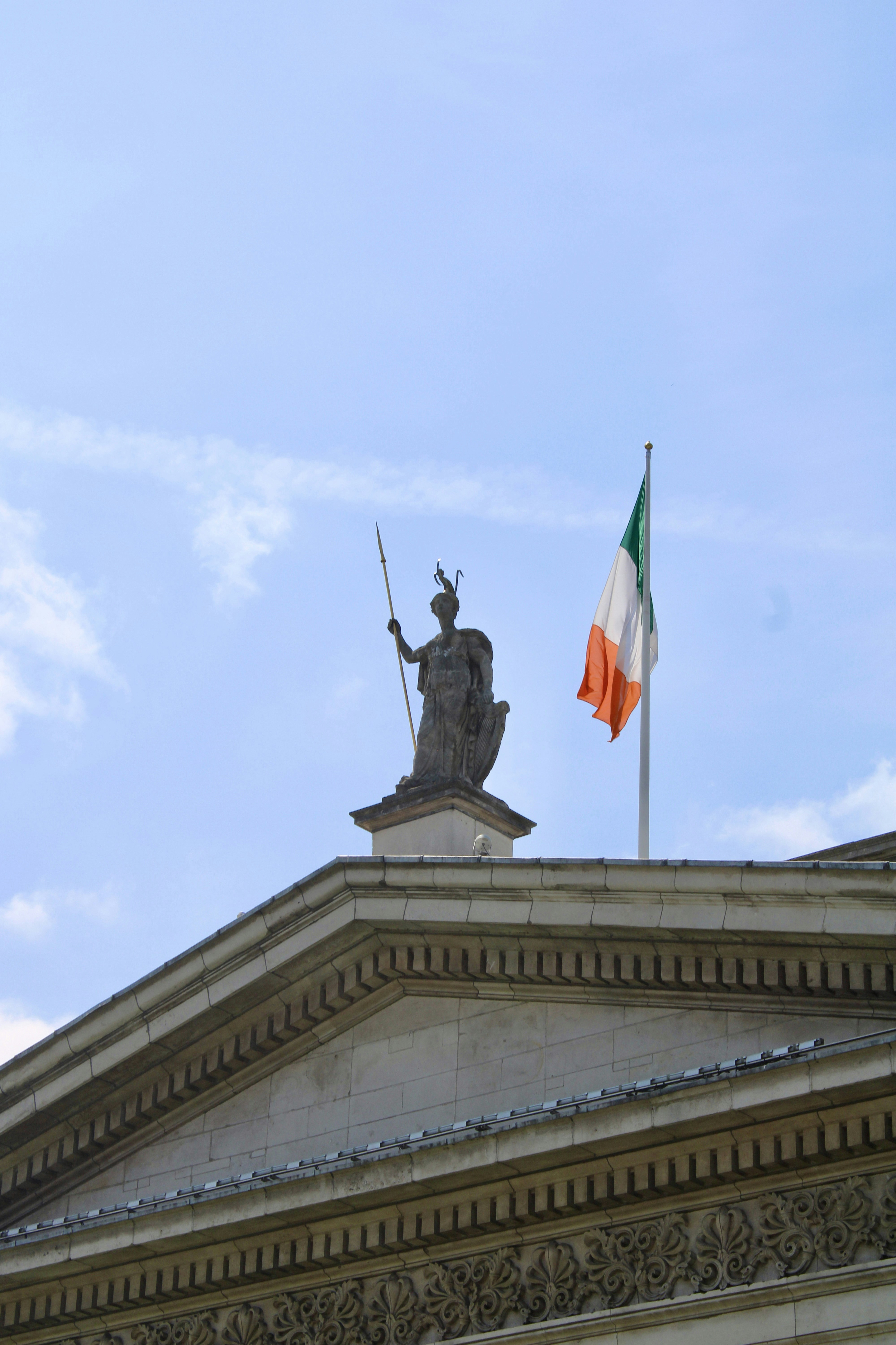 Flag and Statue Above Classic Facade Under A Clear Sky