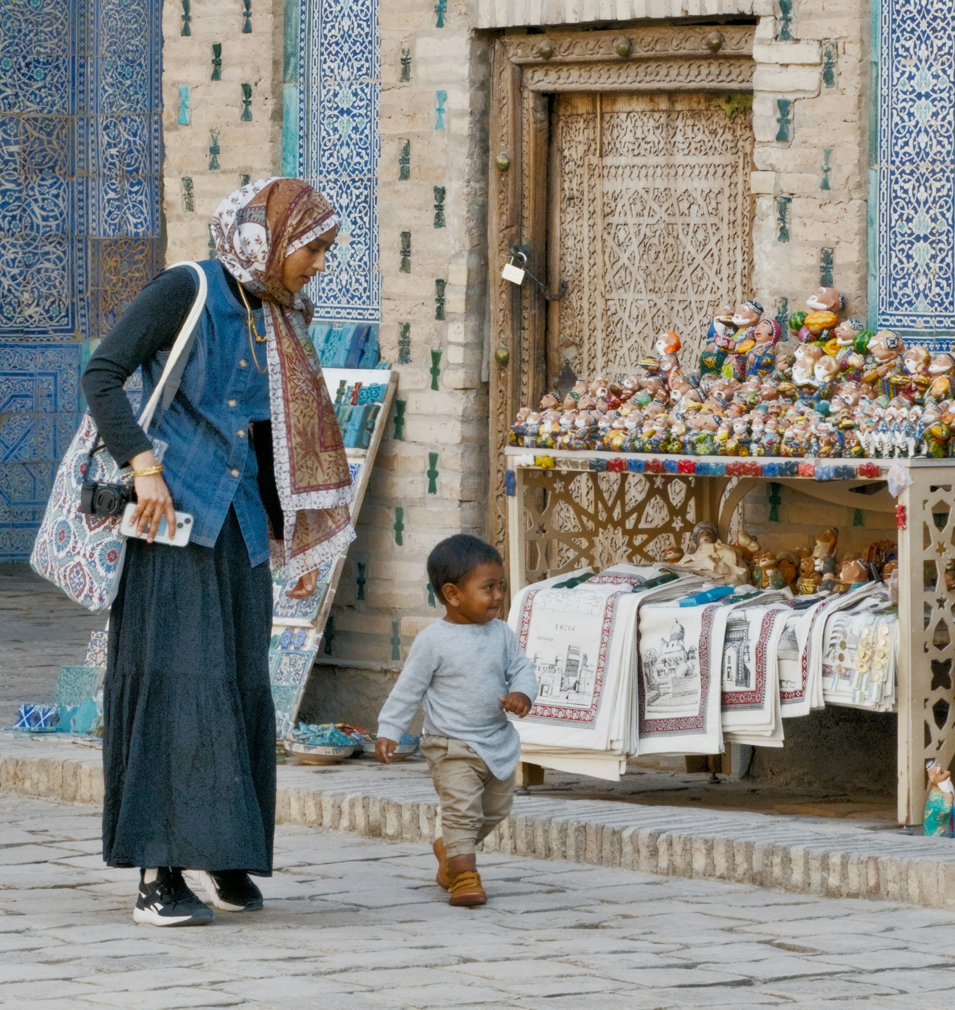 Mother and Child in a Sunlit Bazaar of Carved Tiles