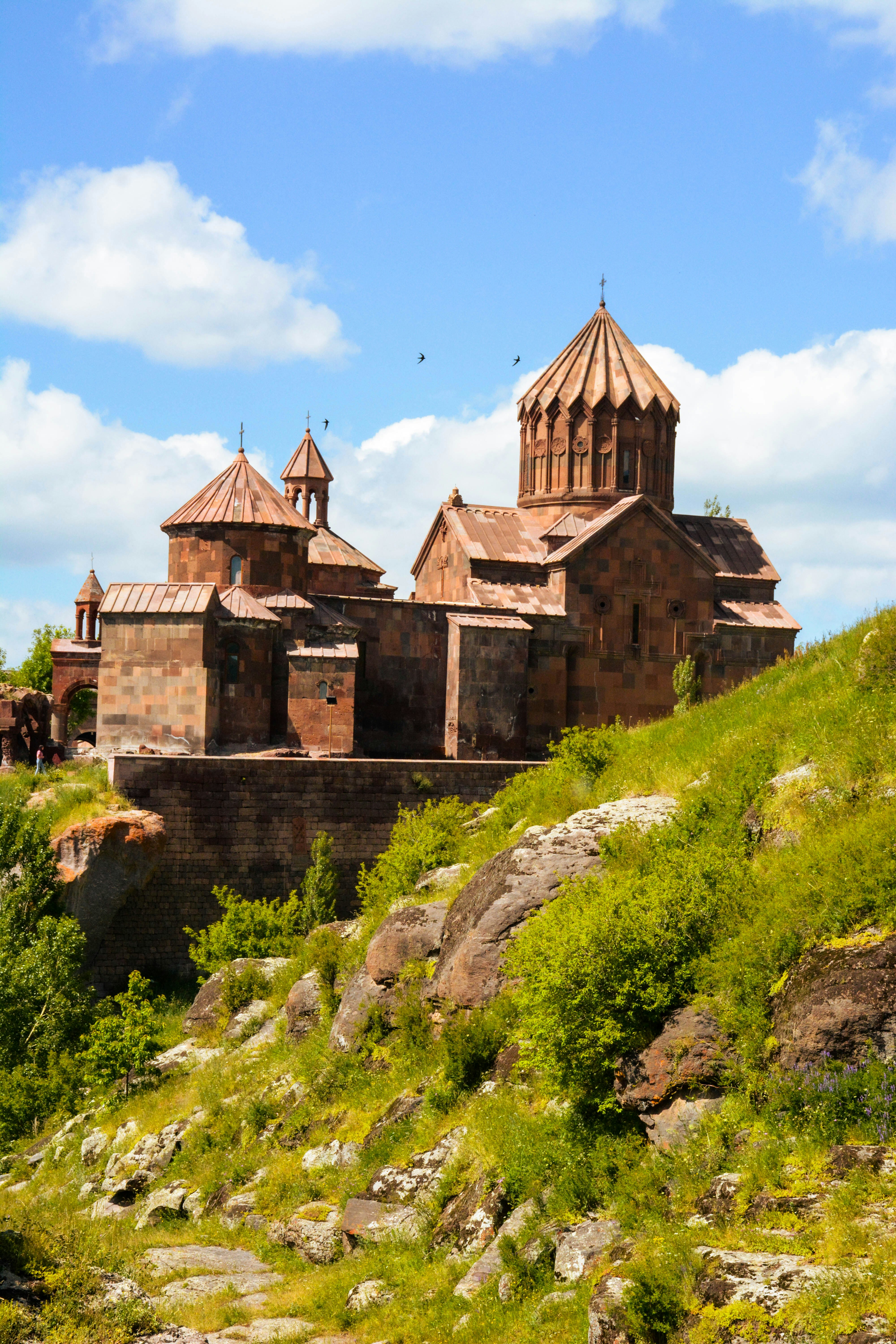 Ruins atop the green hill: a fortress church under a bright sky