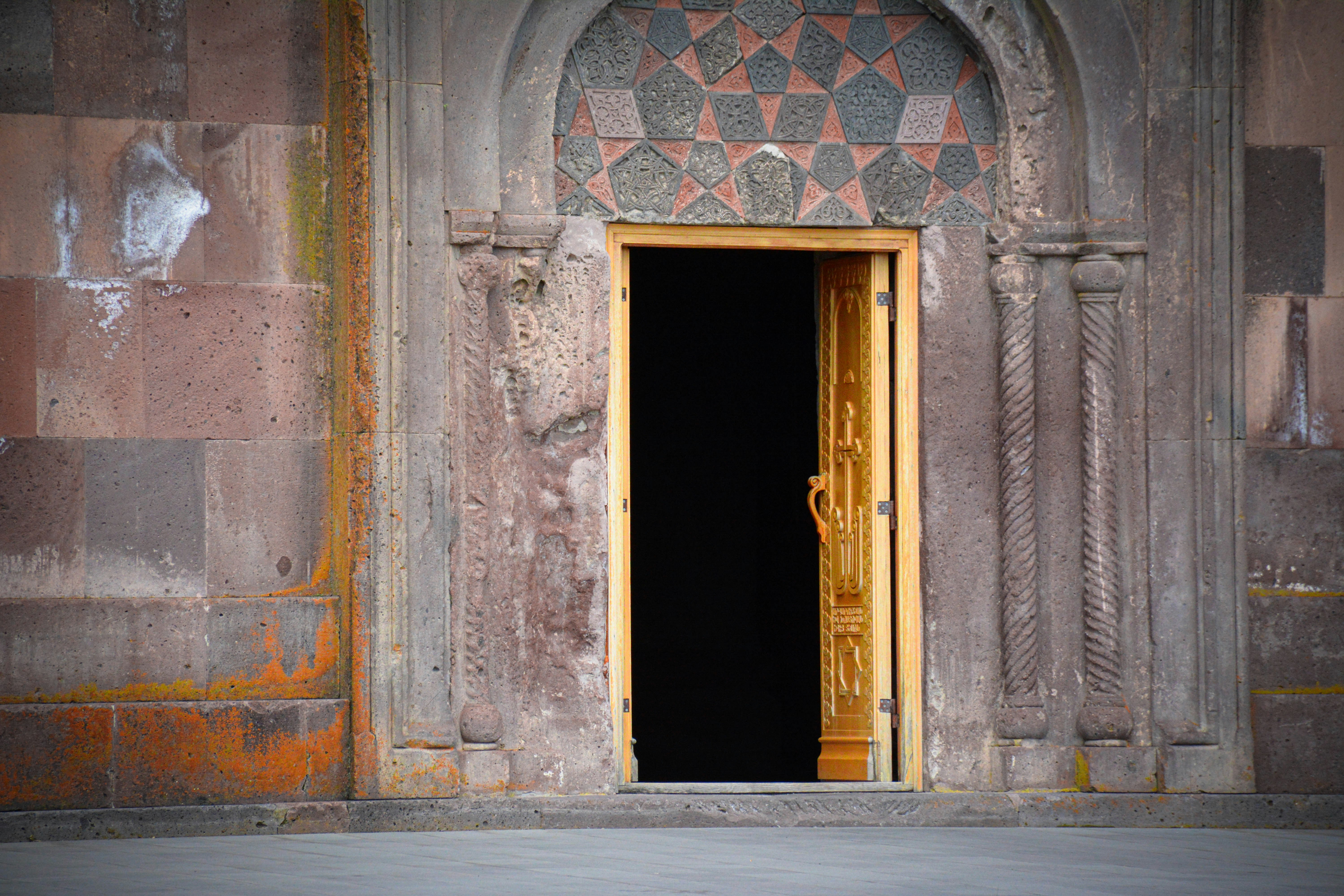 Gateway to Darkness: A Golden Doorway in an Aged Stone Facade
