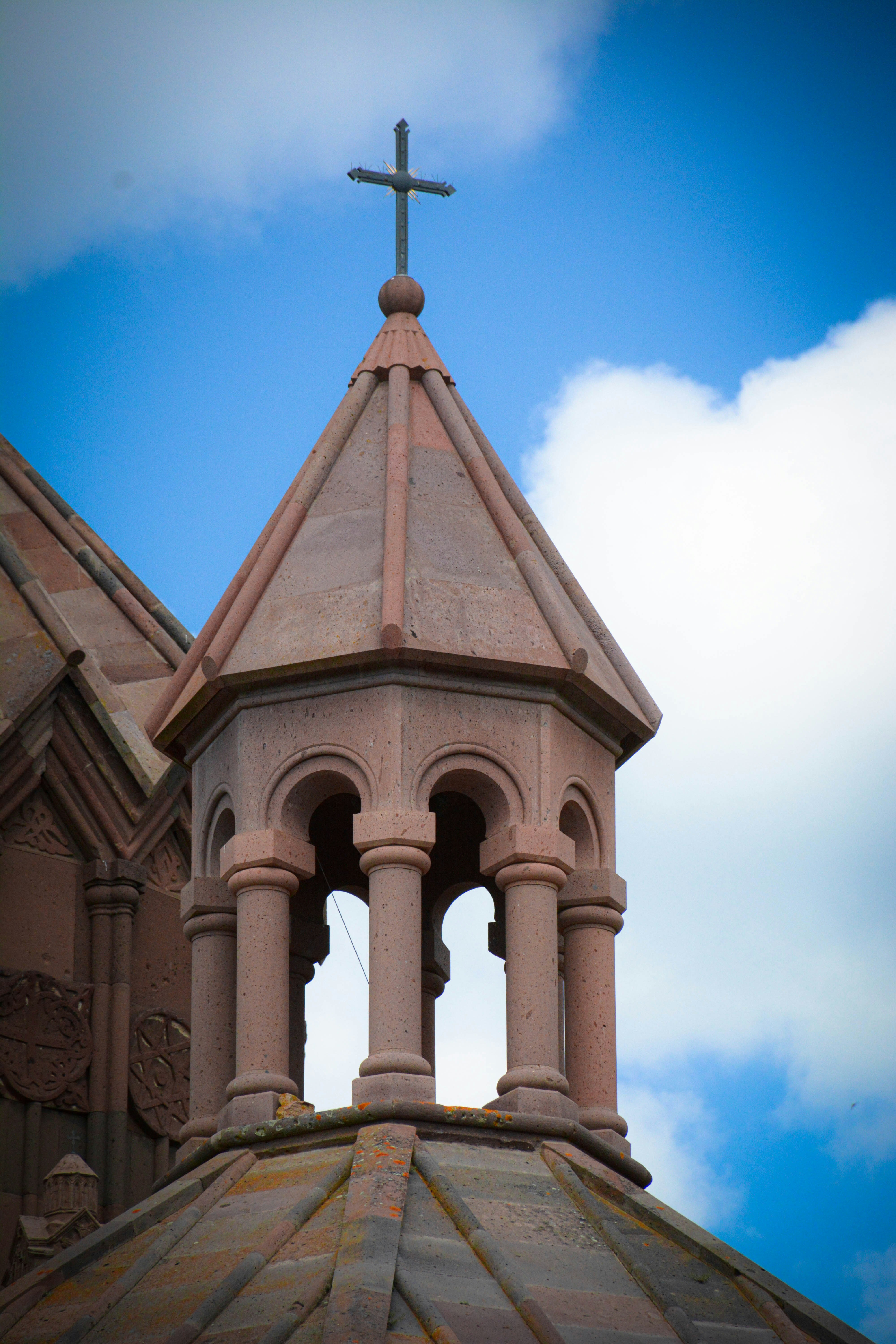 Stone Cross Tower rising above the tiled apex under a blue sky