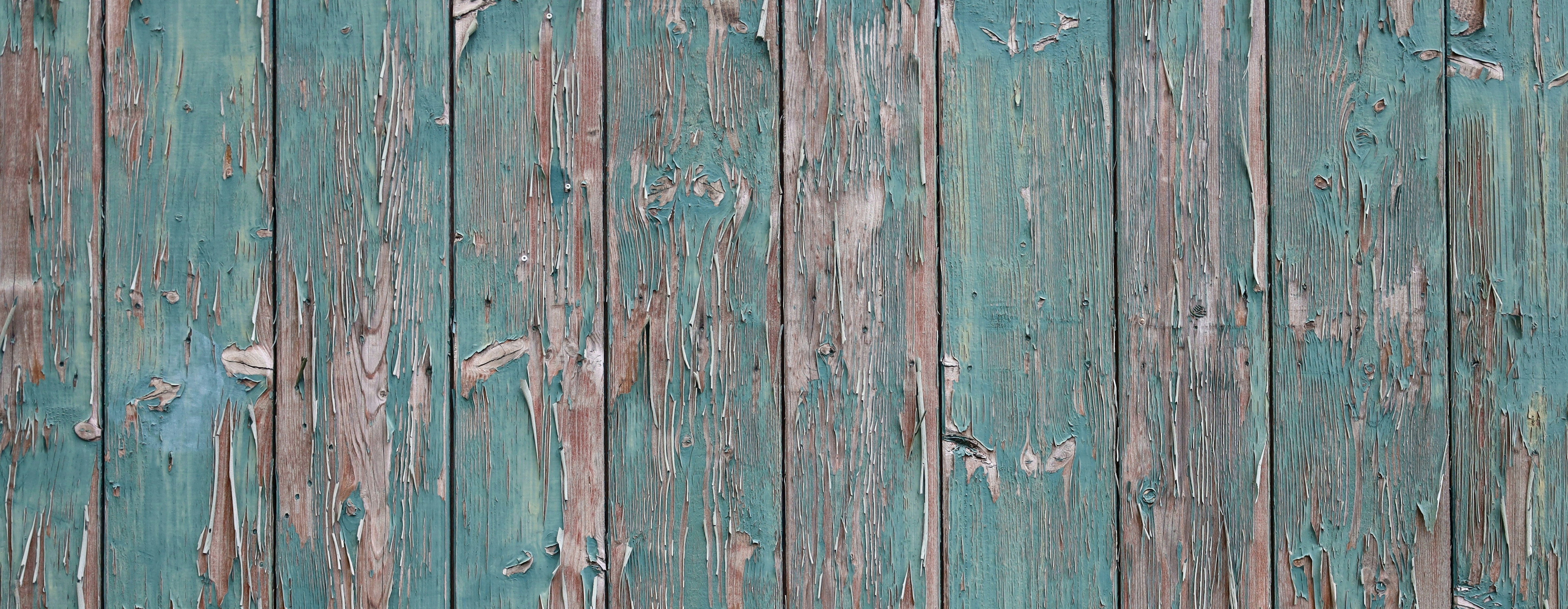 Turquoise wooden planks with peeling paint showing grain and weathering, forming a textured backdrop suitable for design or product shoots.