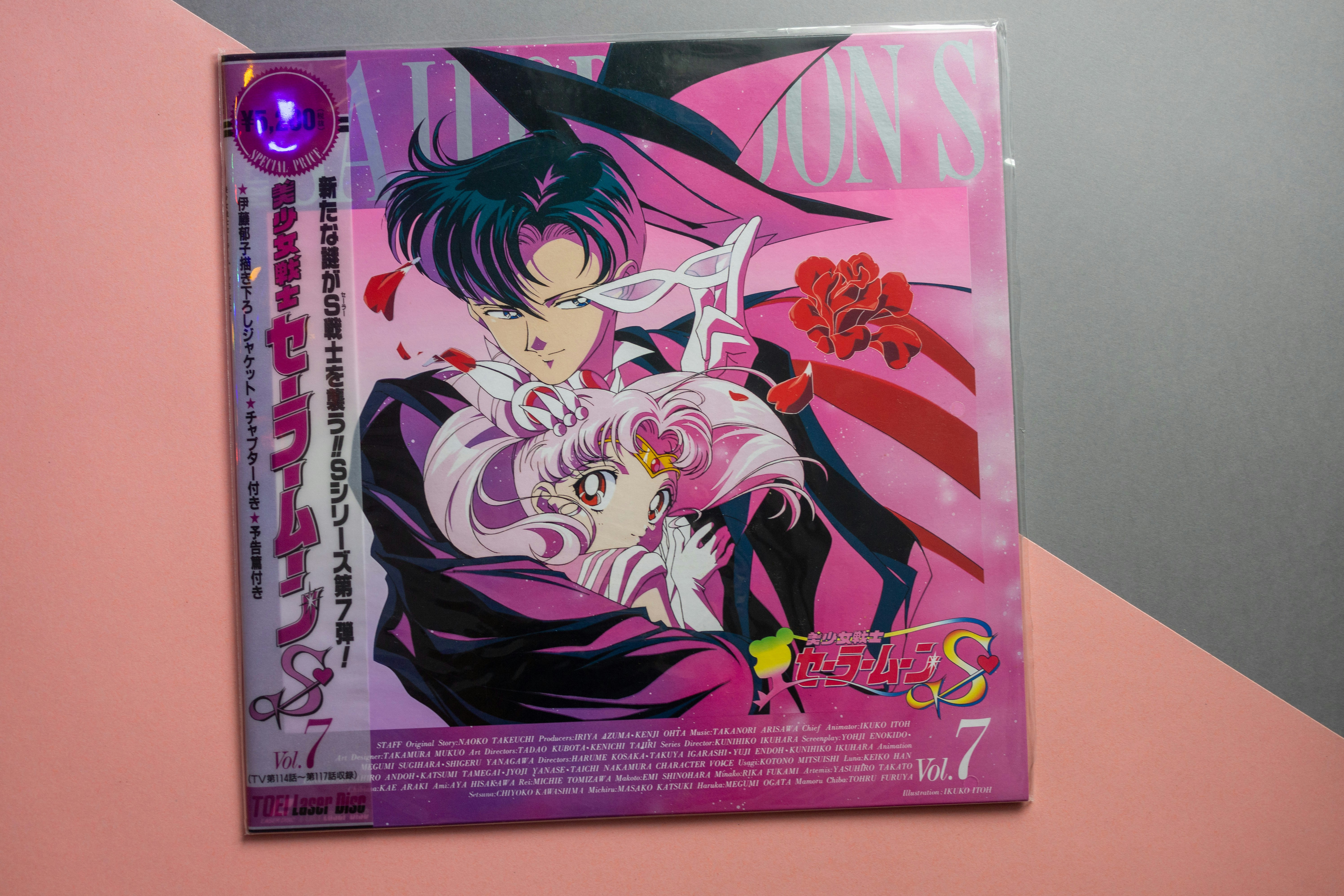 Colorful Sailor Moon CD case resting on a pink and gray background, with Japanese text along the left spine. A vibrant anime illustration dominates the cover.