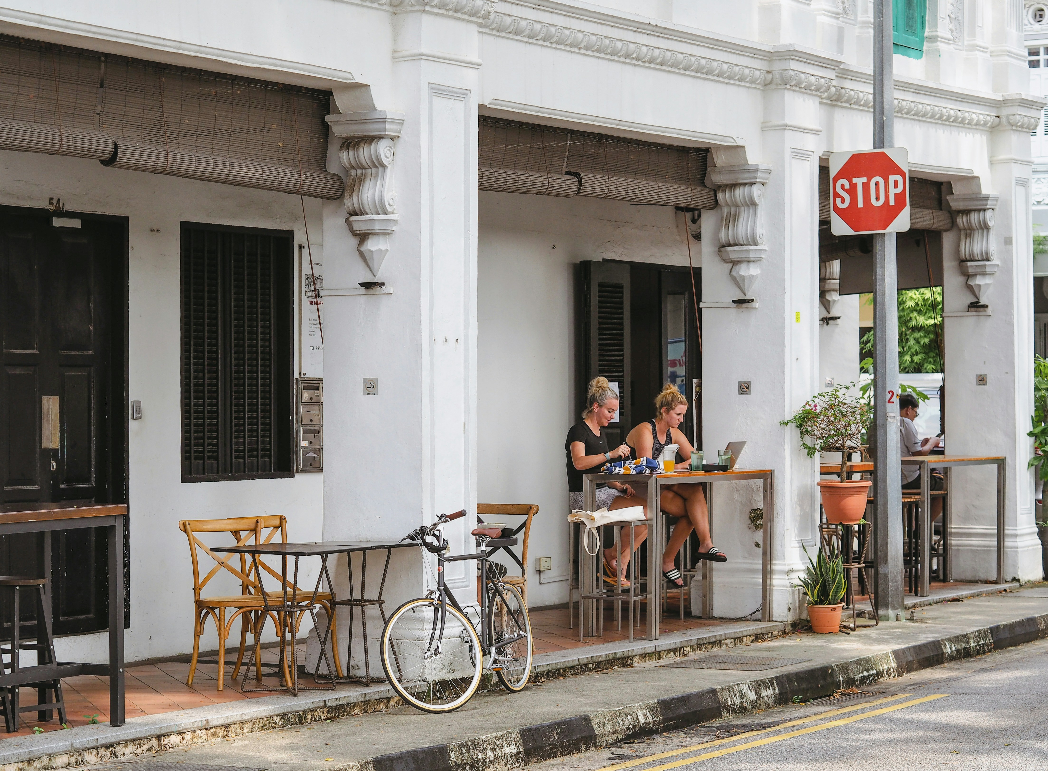 Cafe Front Portrait: Friends at a Sidewalk Table under a Stop Sign