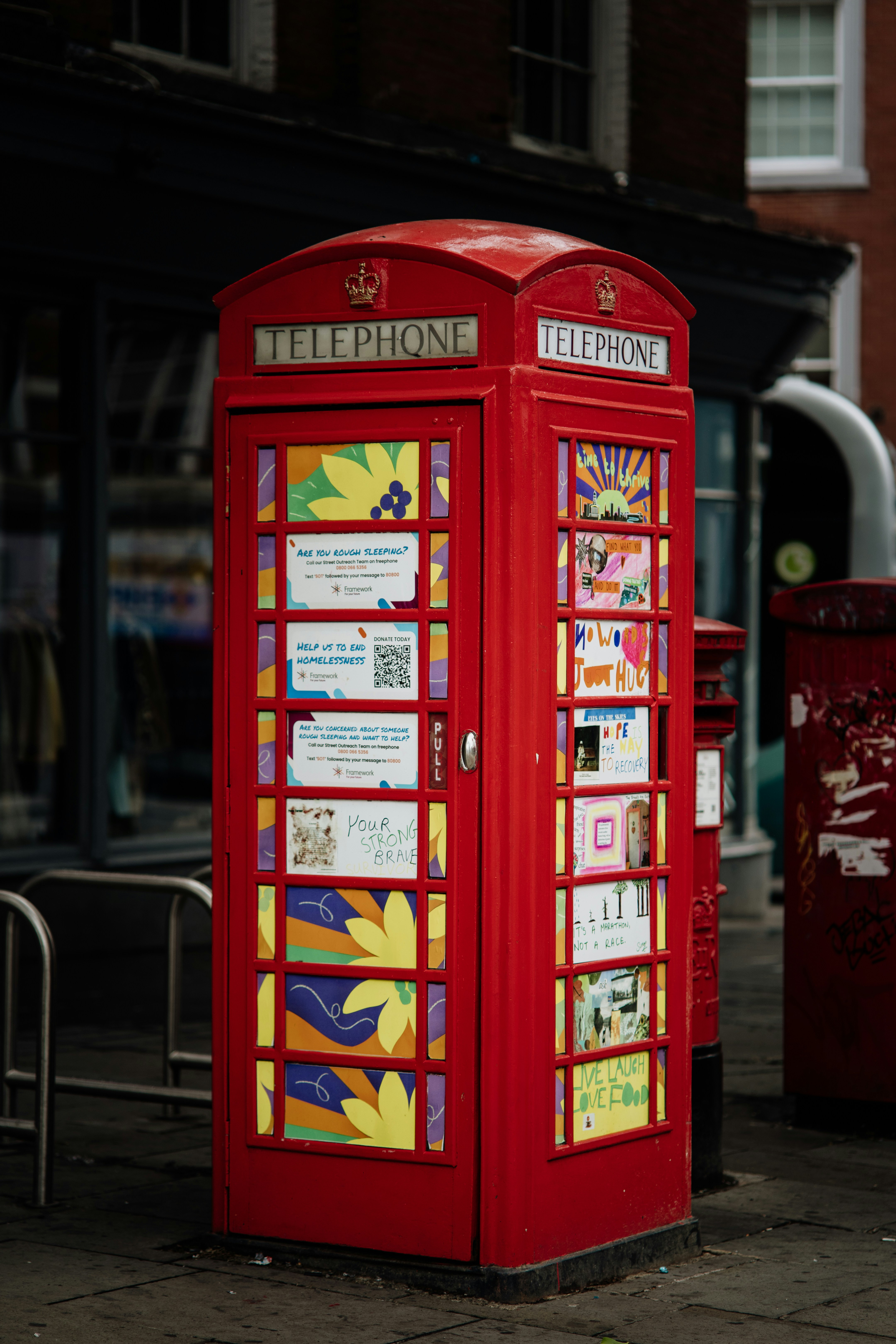 Crimson Post: A Red British Telephone Kiosk Brimming with Colorful Notices