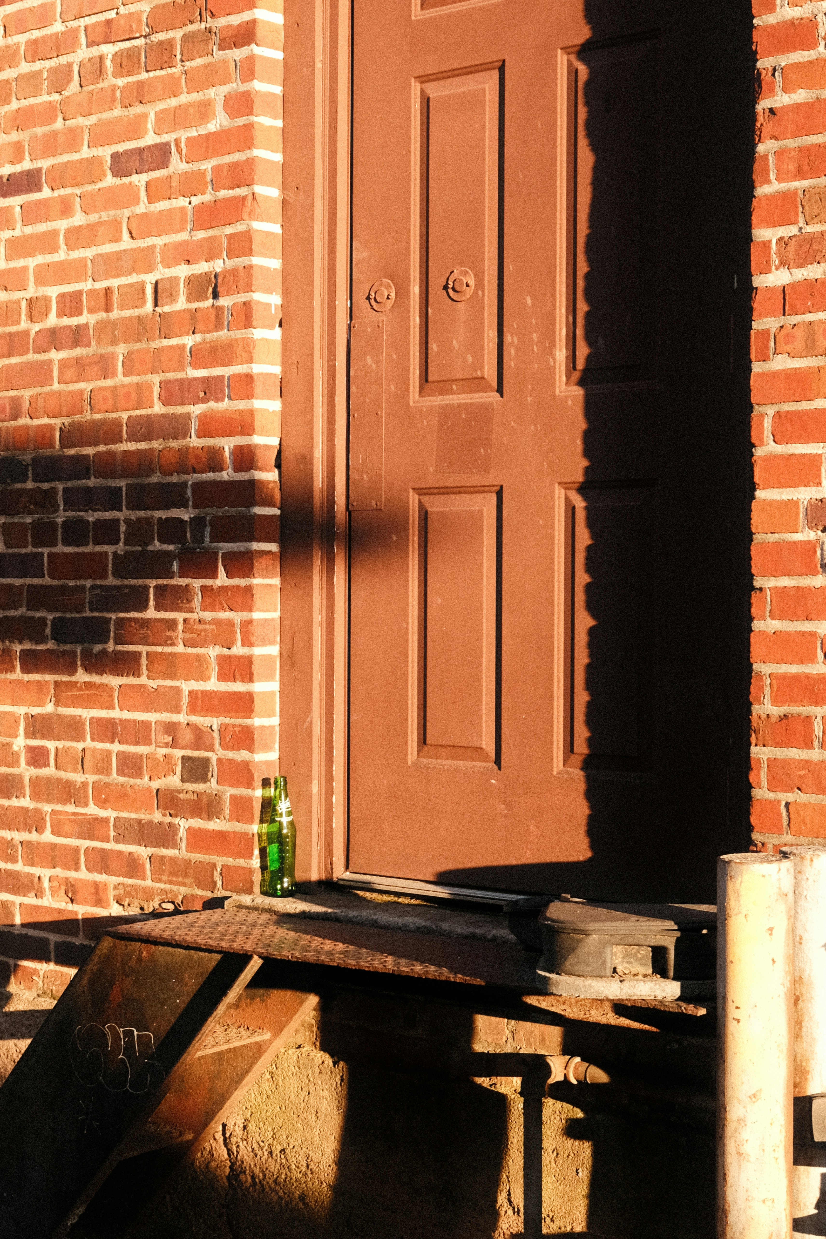 Rust and Shadow: Sunlit Door on a Brick Staircase