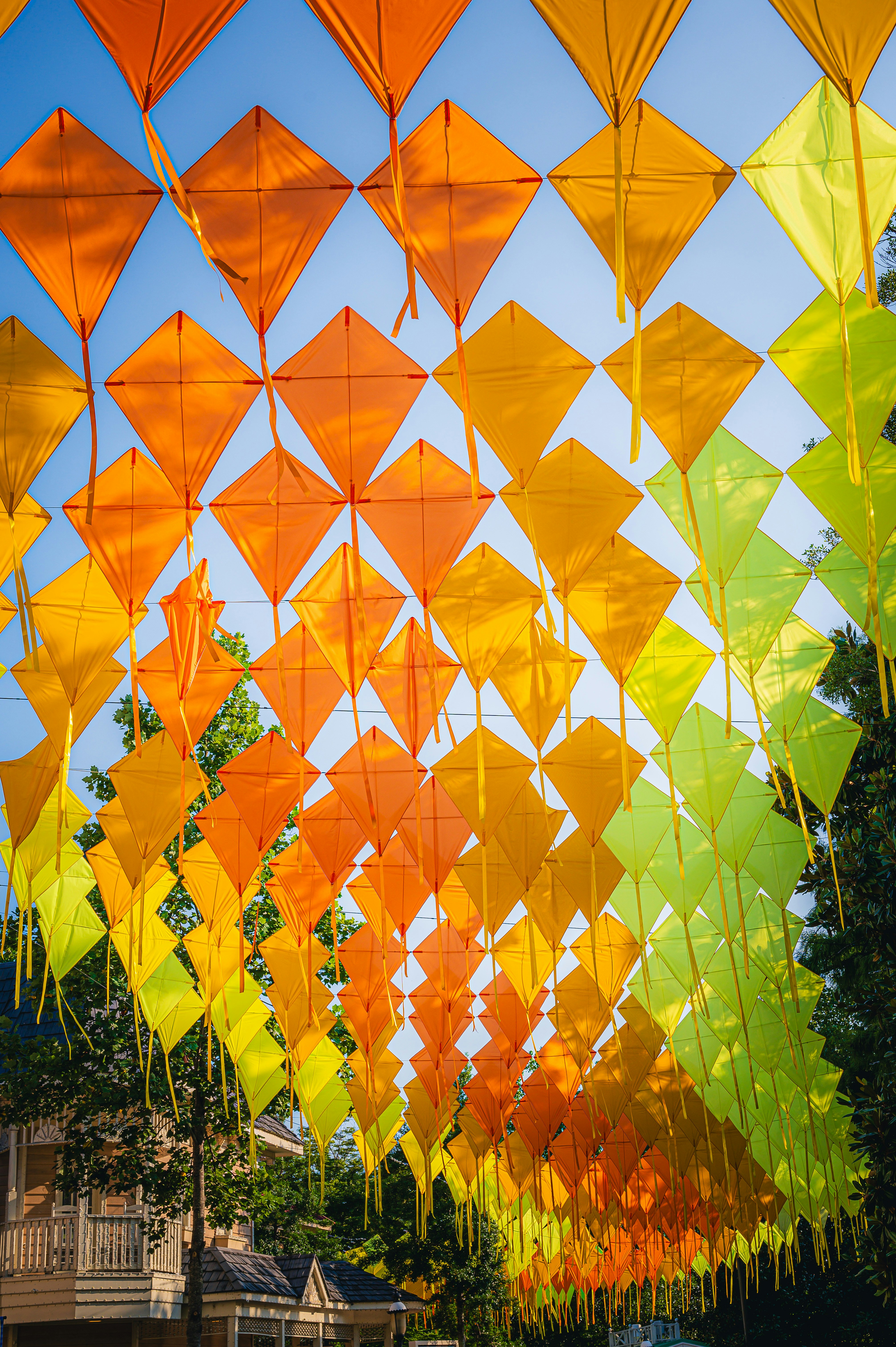 Kaleidoscope Canopy: A Street of Colorful Kites Over a Quiet Roofline