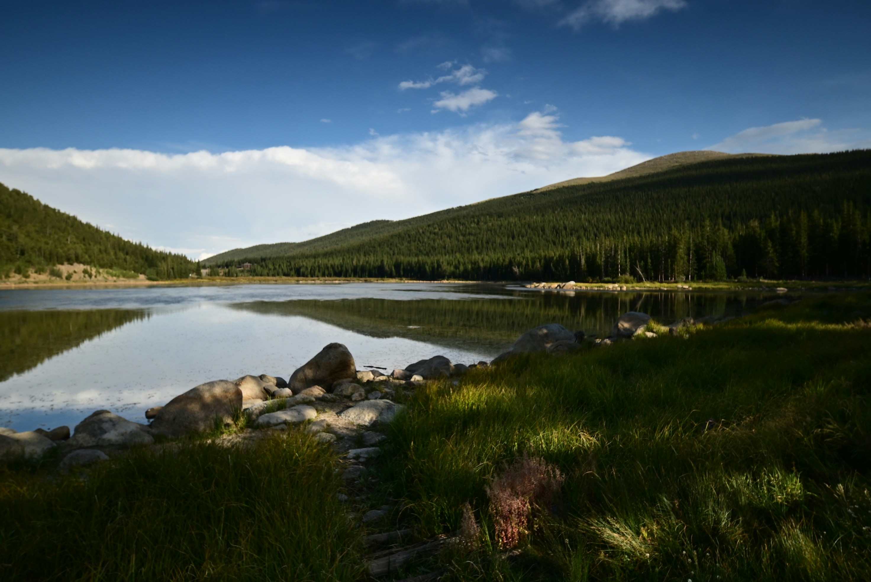 Mirror of the Valley: Stones, Lake, and Pines Beneath a Clear Sky
