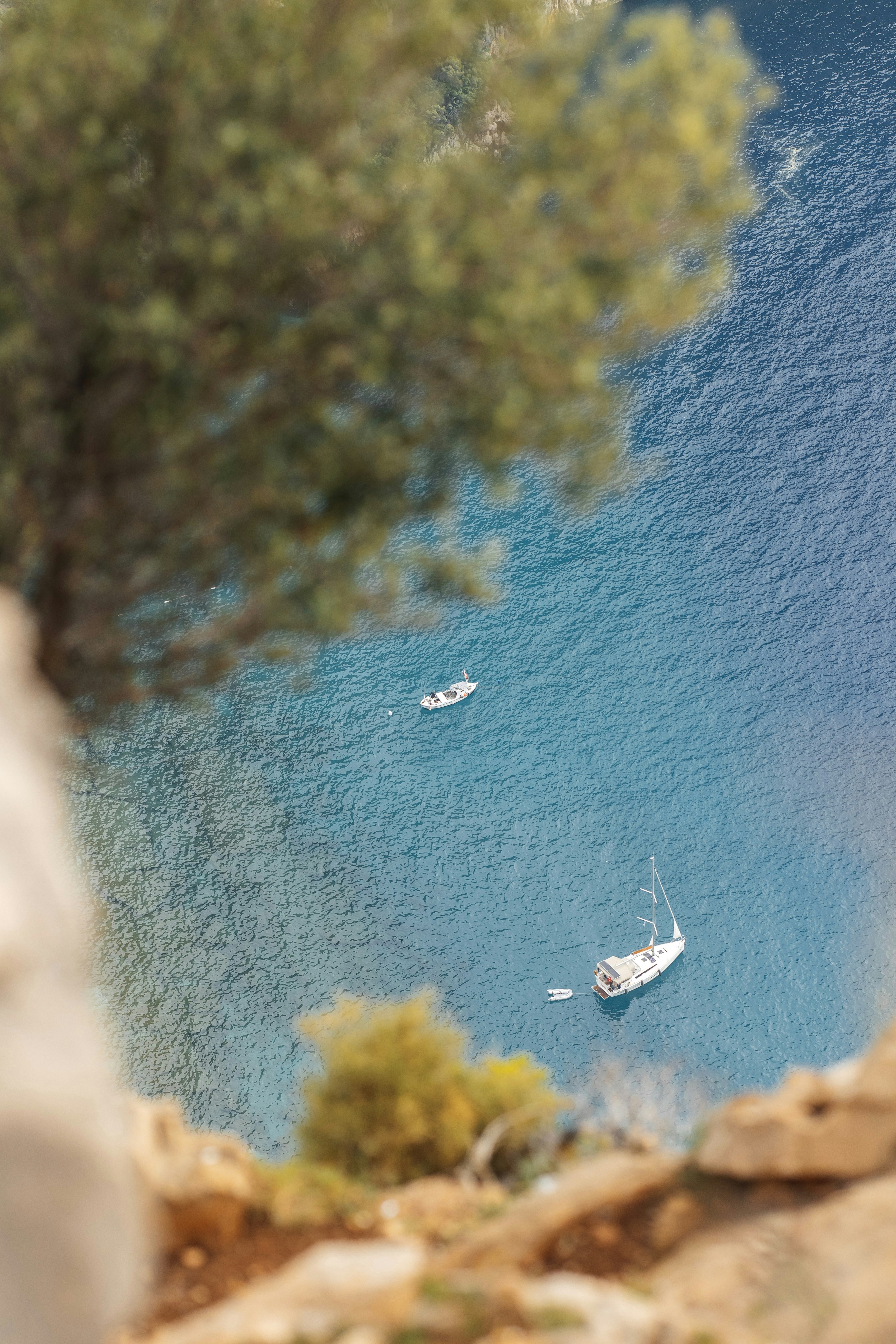 Aerial Blue: Boats at Sea Through a Cliffside Frame
