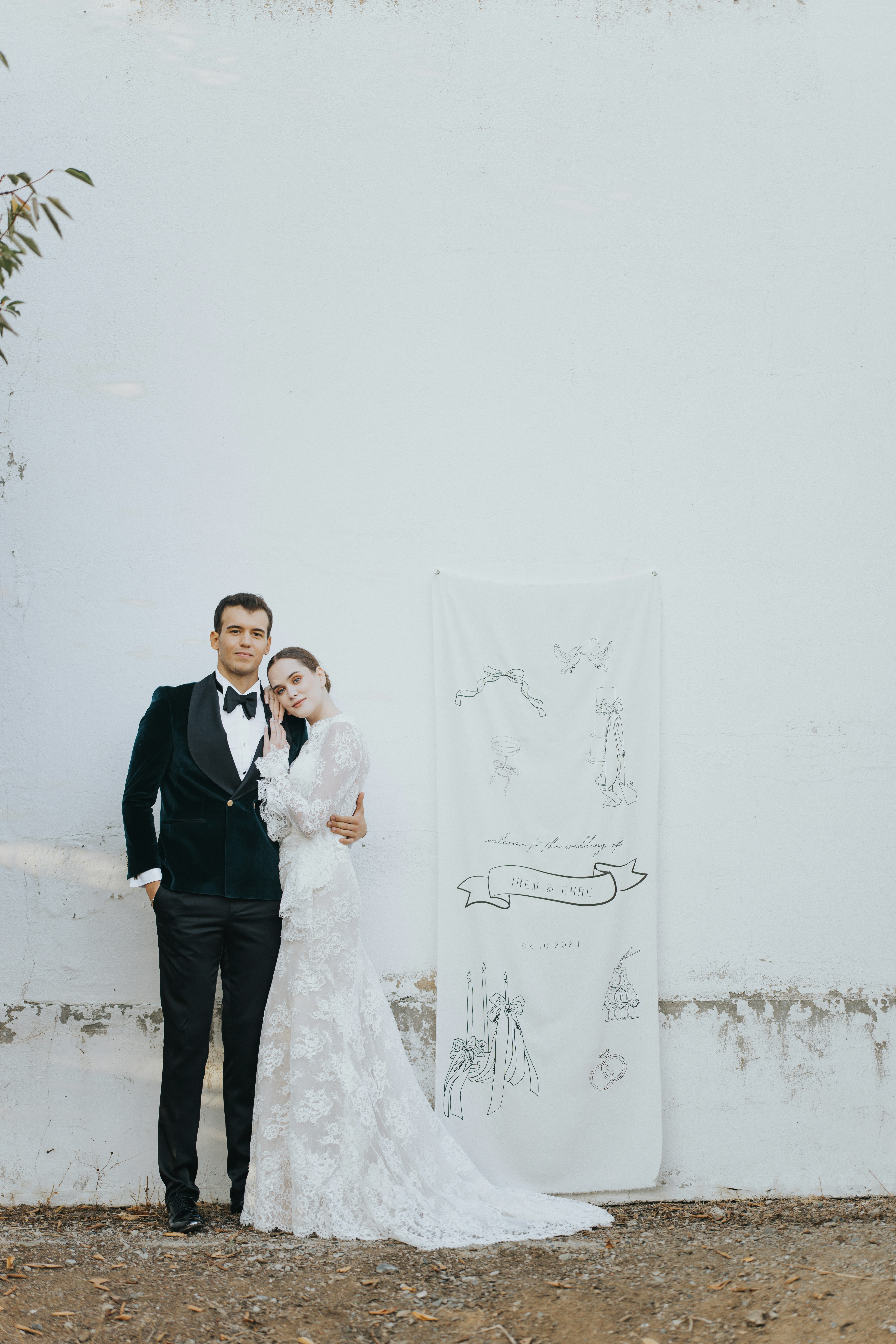 Elegant vows under a pale wall: a newlywed moment beside a decorative banner