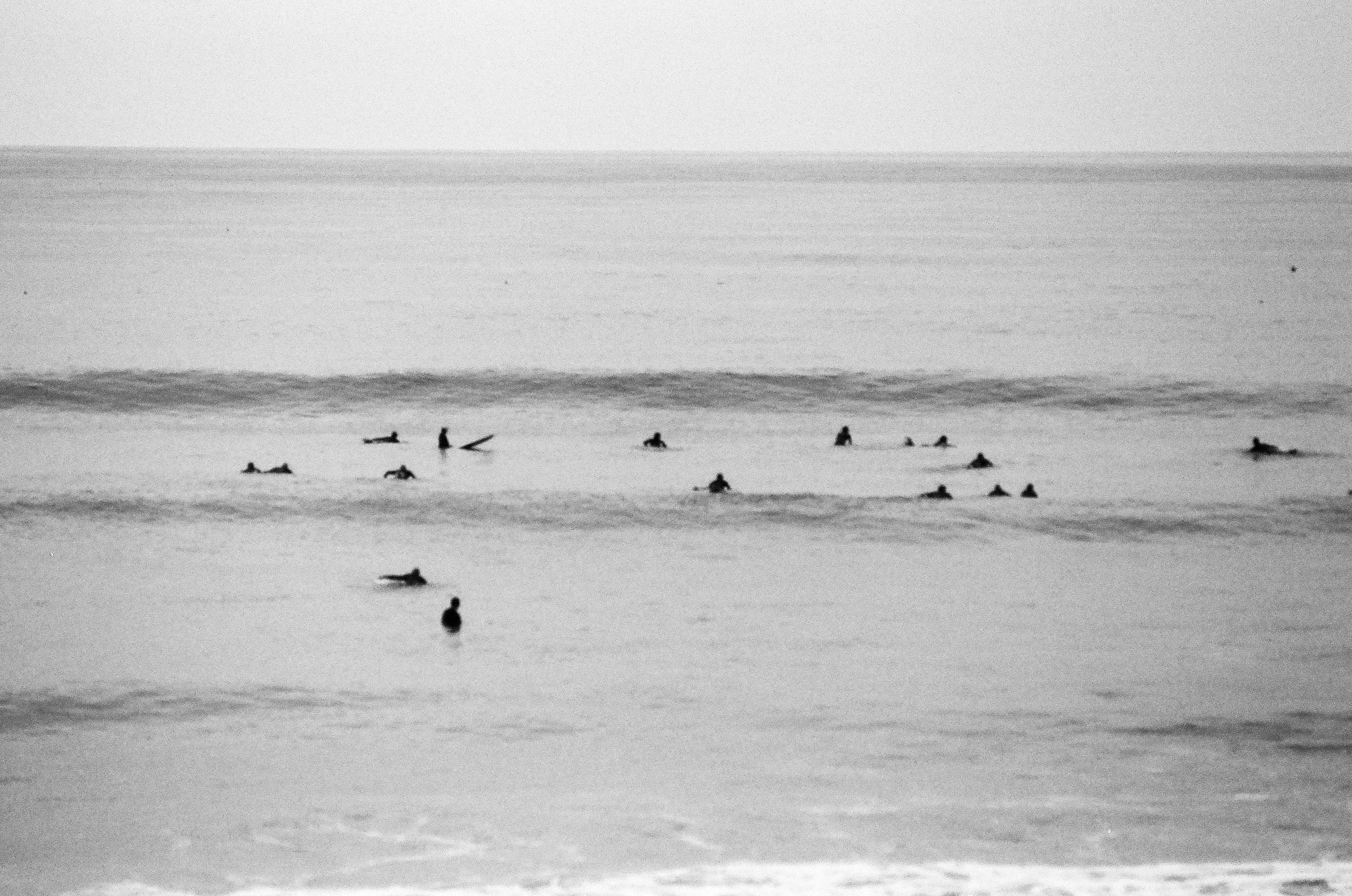 Pastel Tide: Distant Surfers in a Quiet Horizon