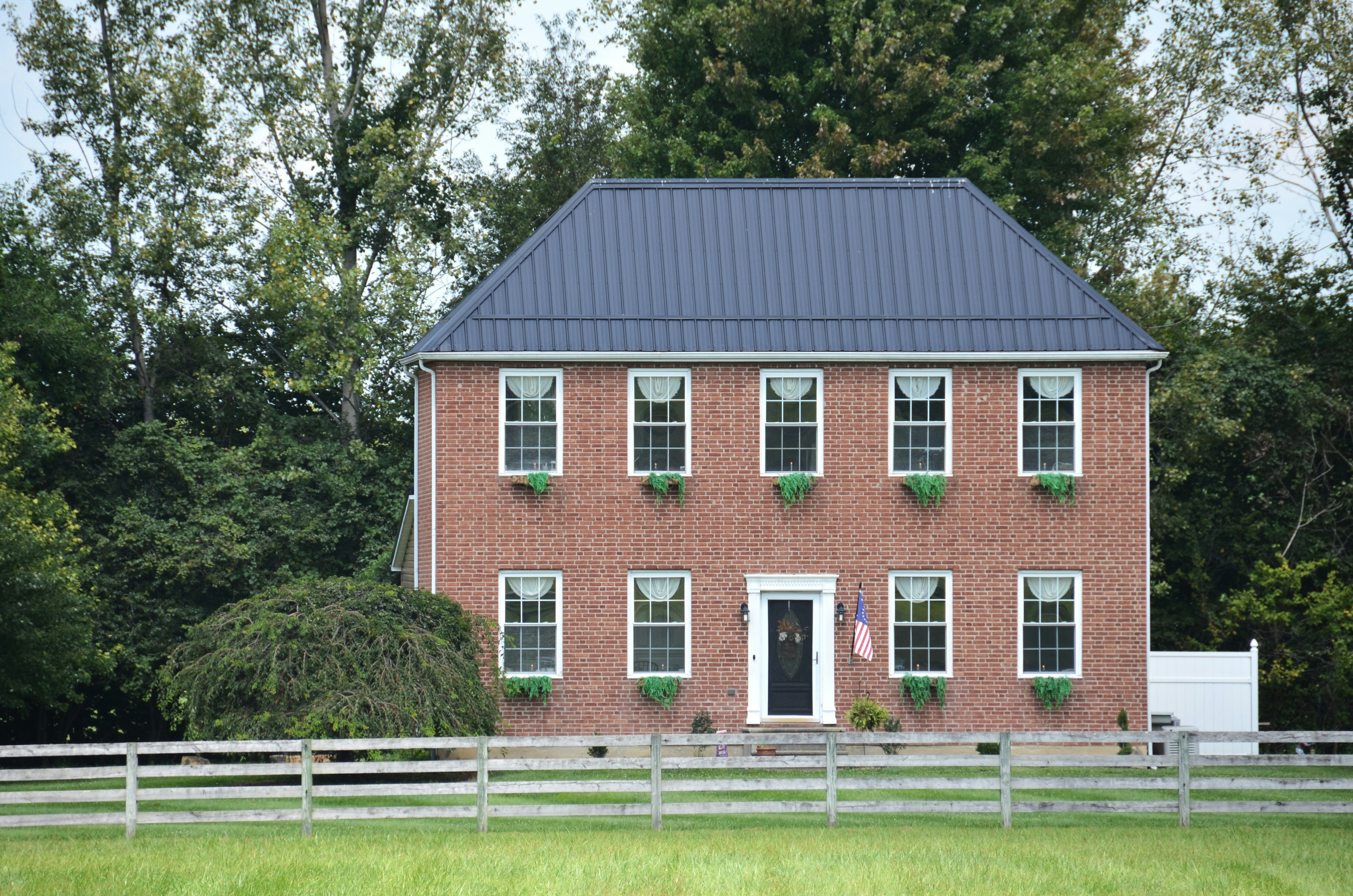 Red Brick House with Symmetrical Window Plan and White Pickett Fence