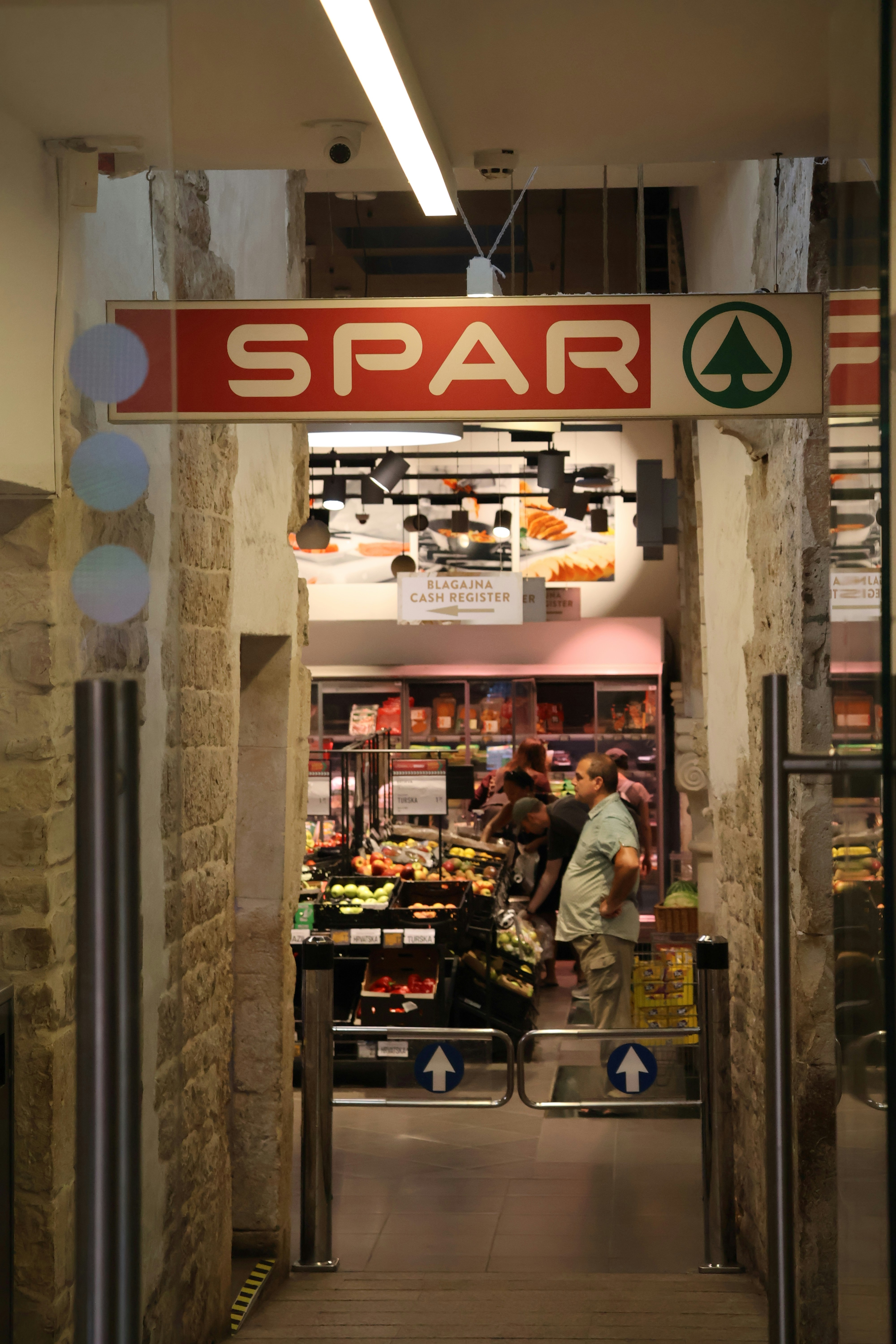 Spar Quiet Entrance: A Grocery Aisle Framed by Stone