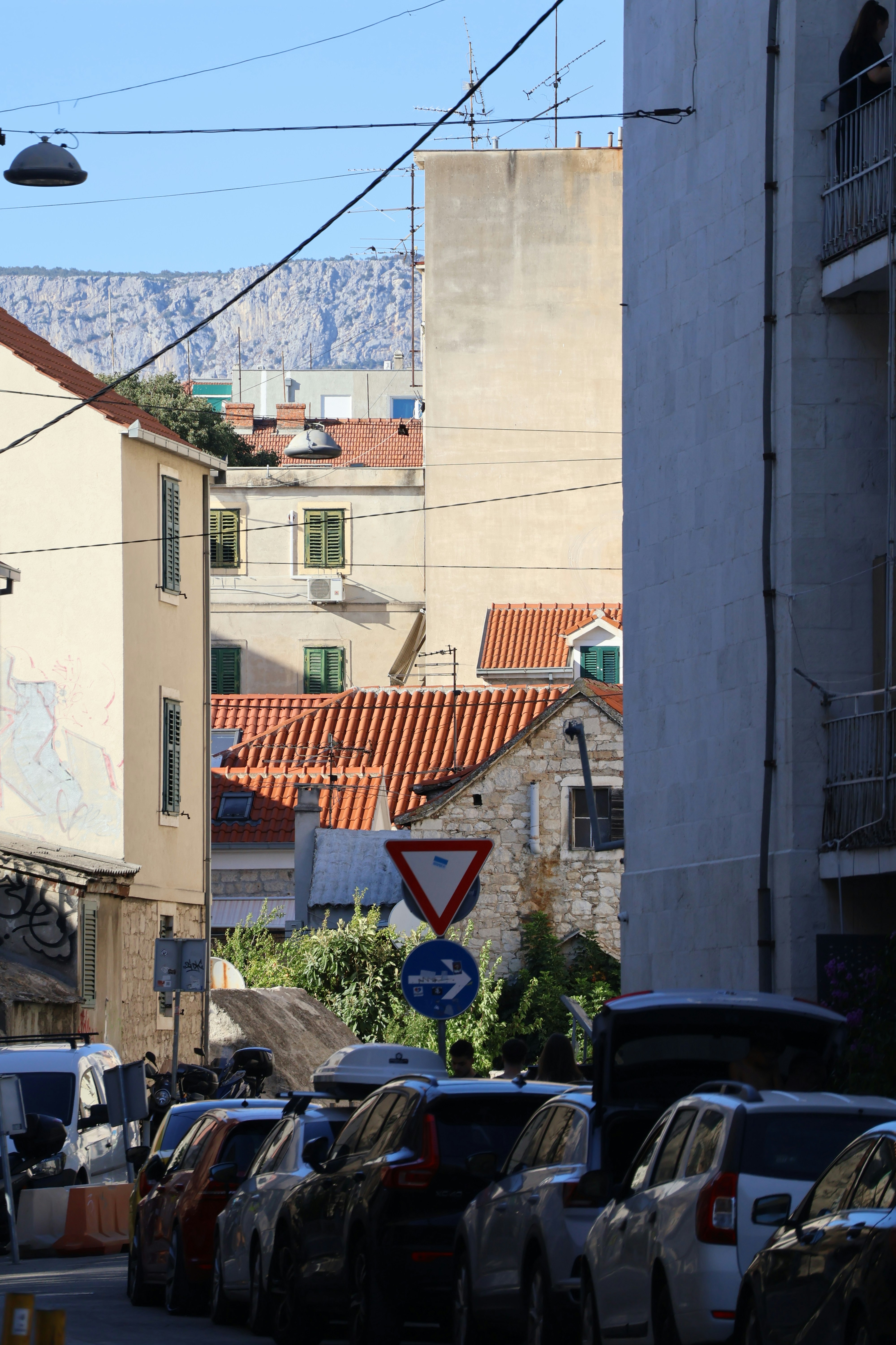 Narrow street in a sunlit Mediterranean town framed by terracotta roofs