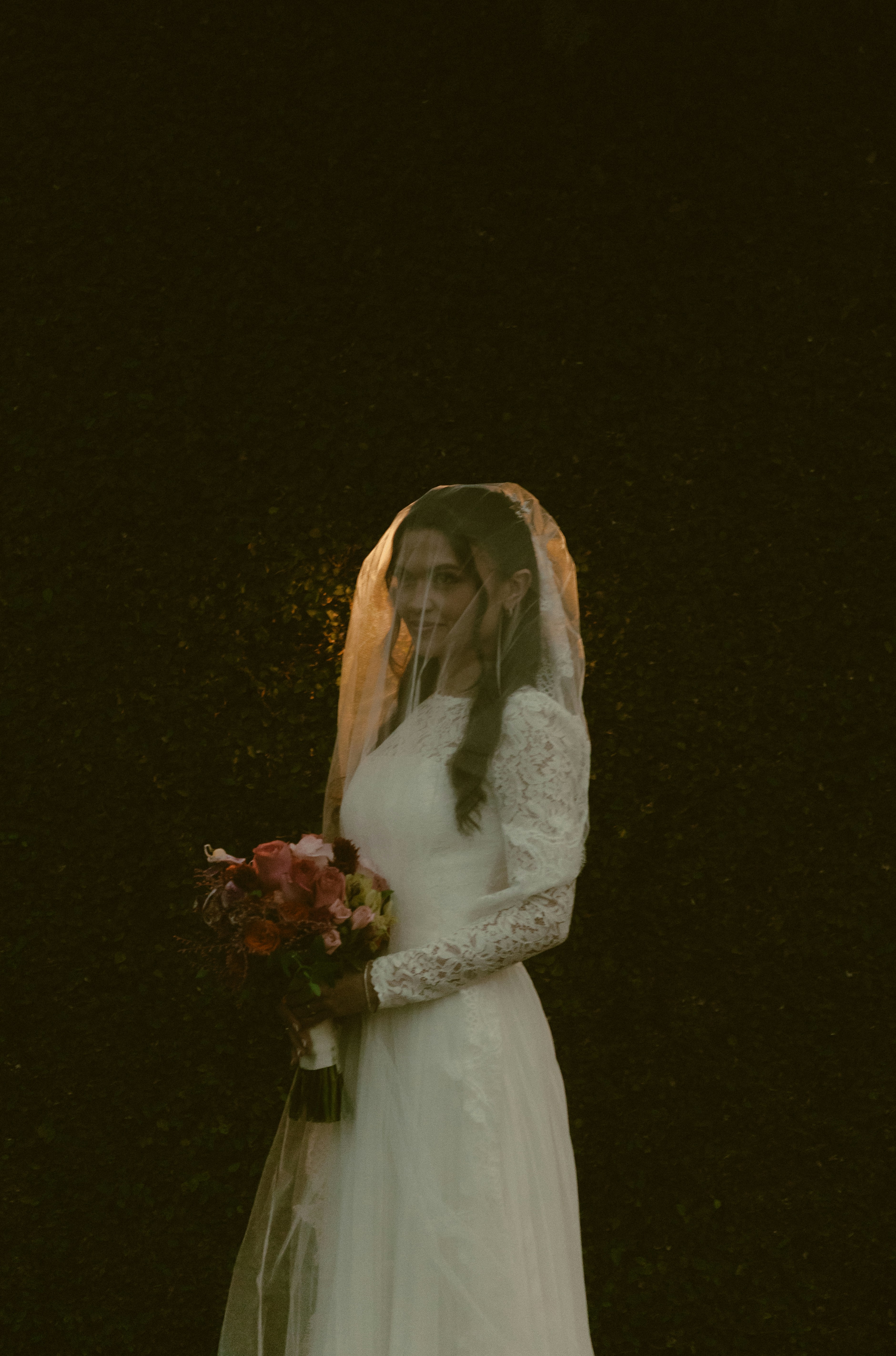 Veil of Night: A Bride in Soft Light Holding Summer Bouquets
