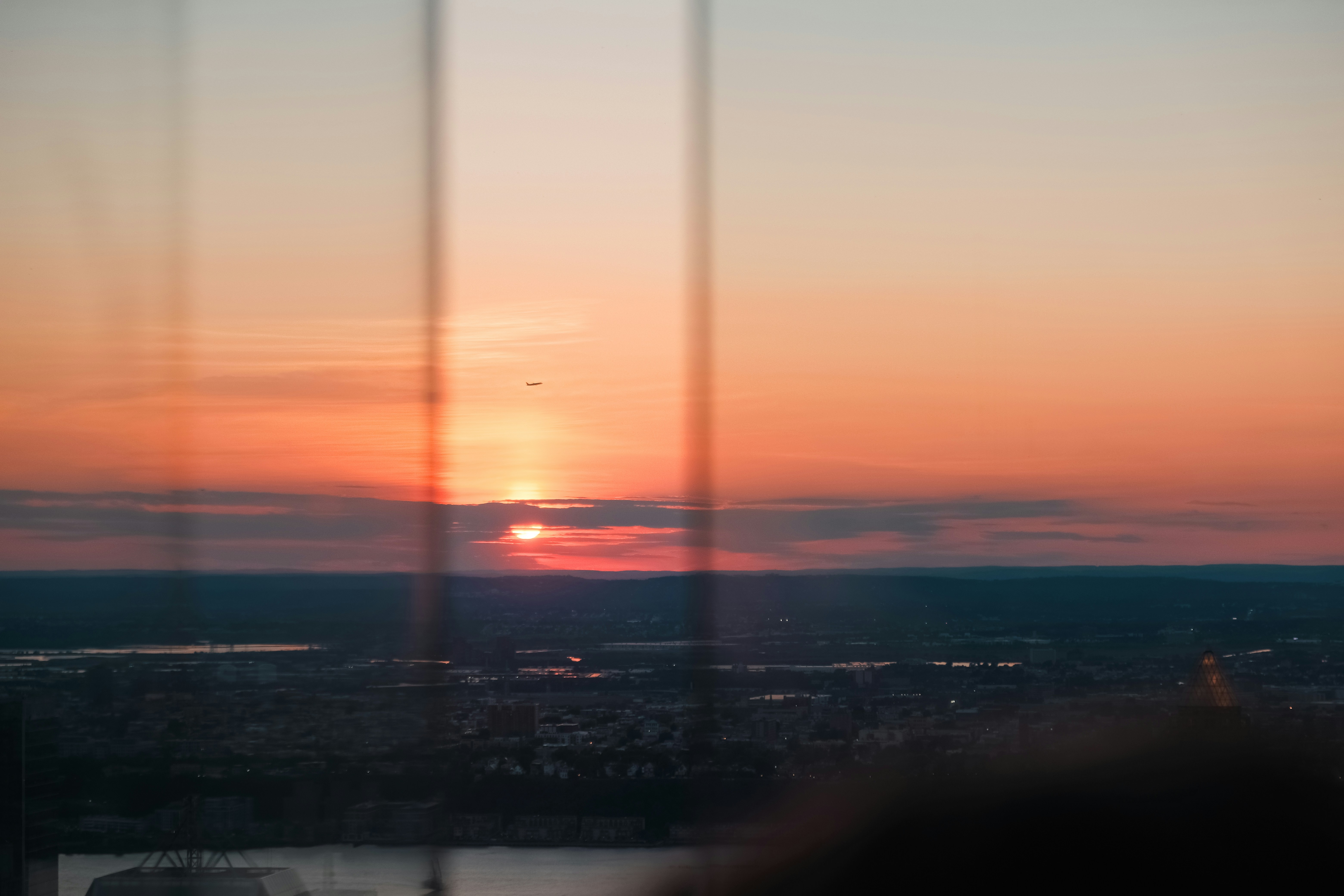 Sunset Between Glass: A City Silhouette through Curtain Reflections