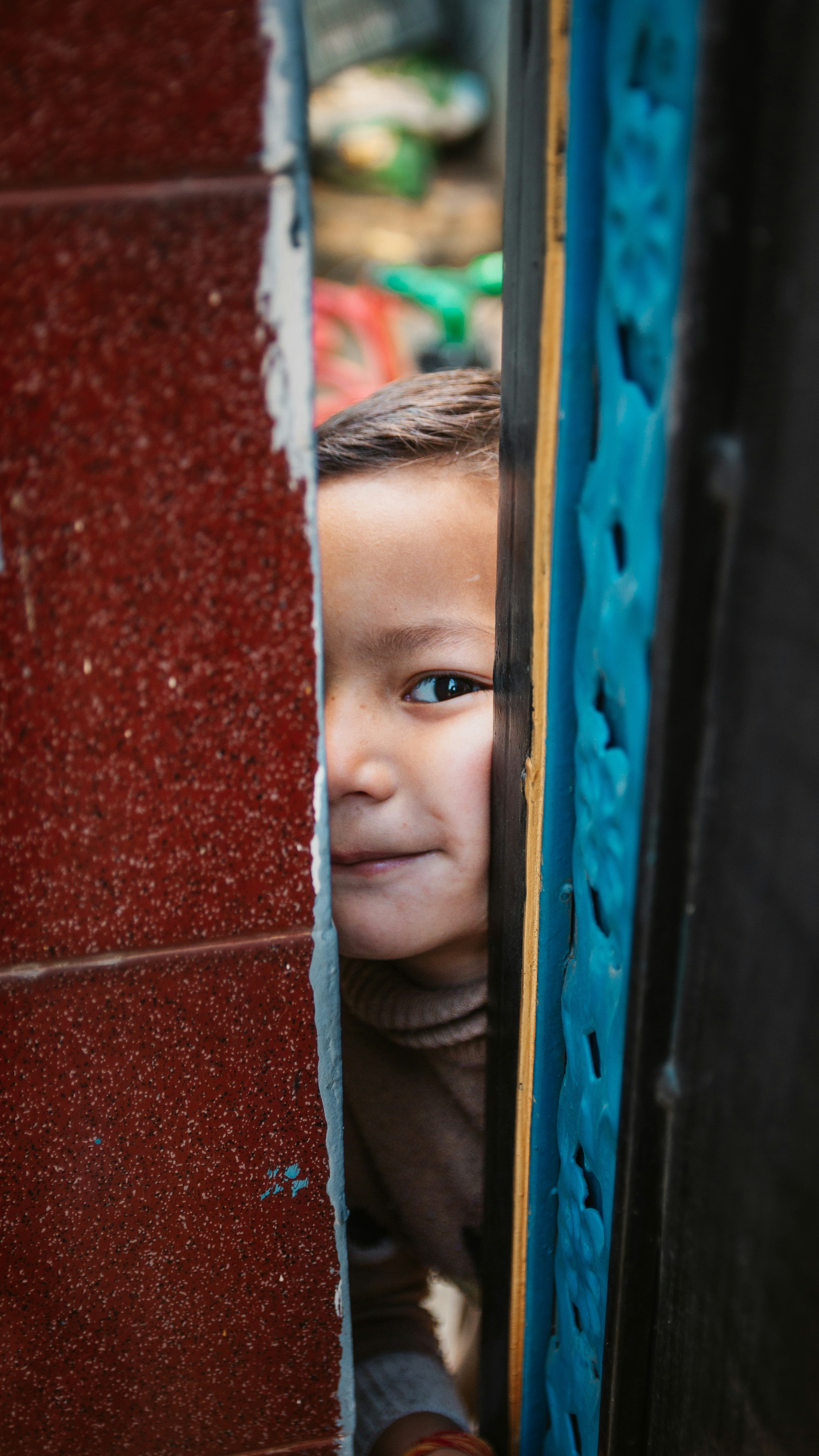 Peek Between Colors: A Child’s Hidden Smile Peeks Through Narrow Gaps