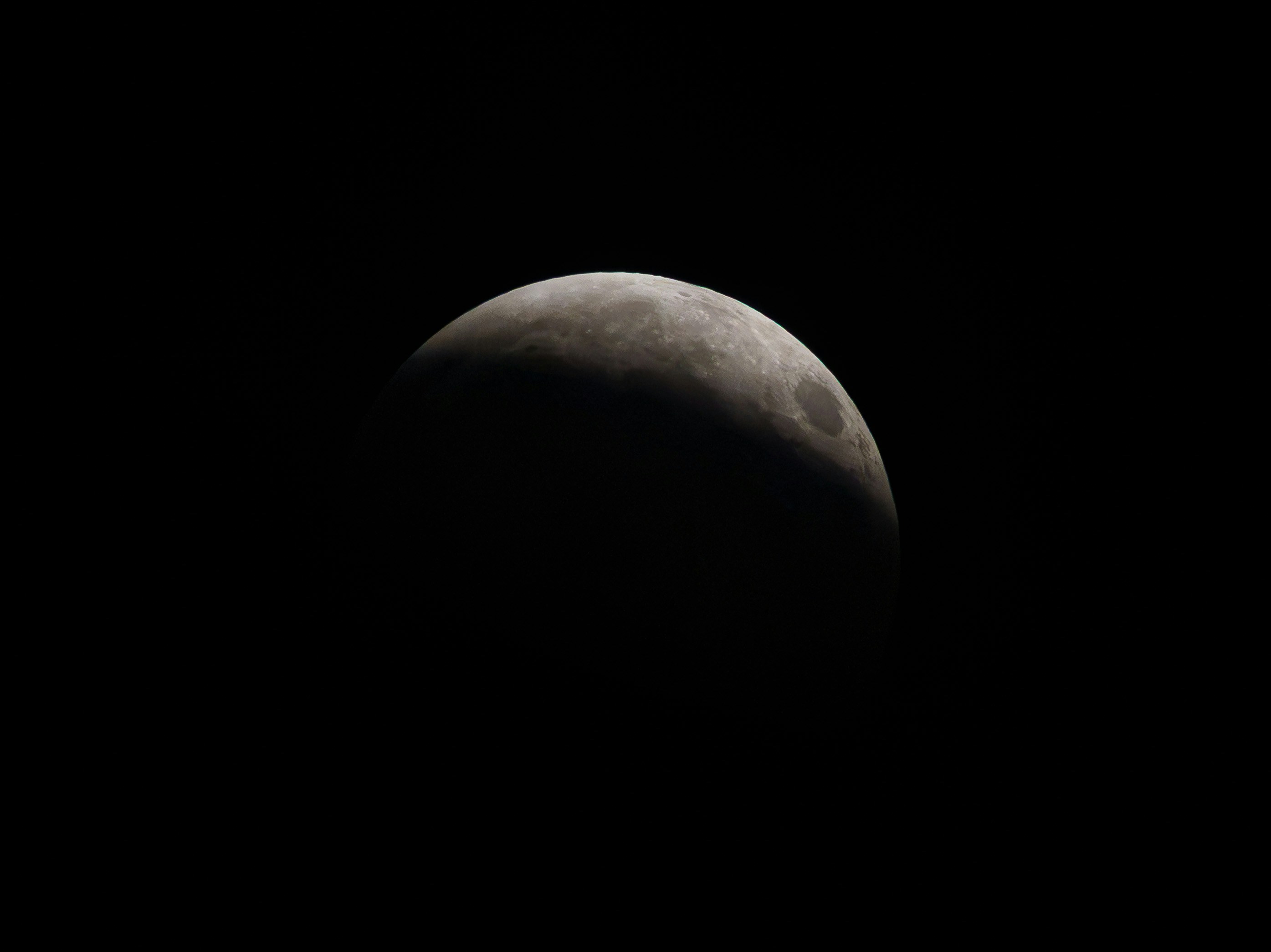 Partial lunar eclipse showing the Earth’s shadow moving across the surface of the Moon against a dark night sky.