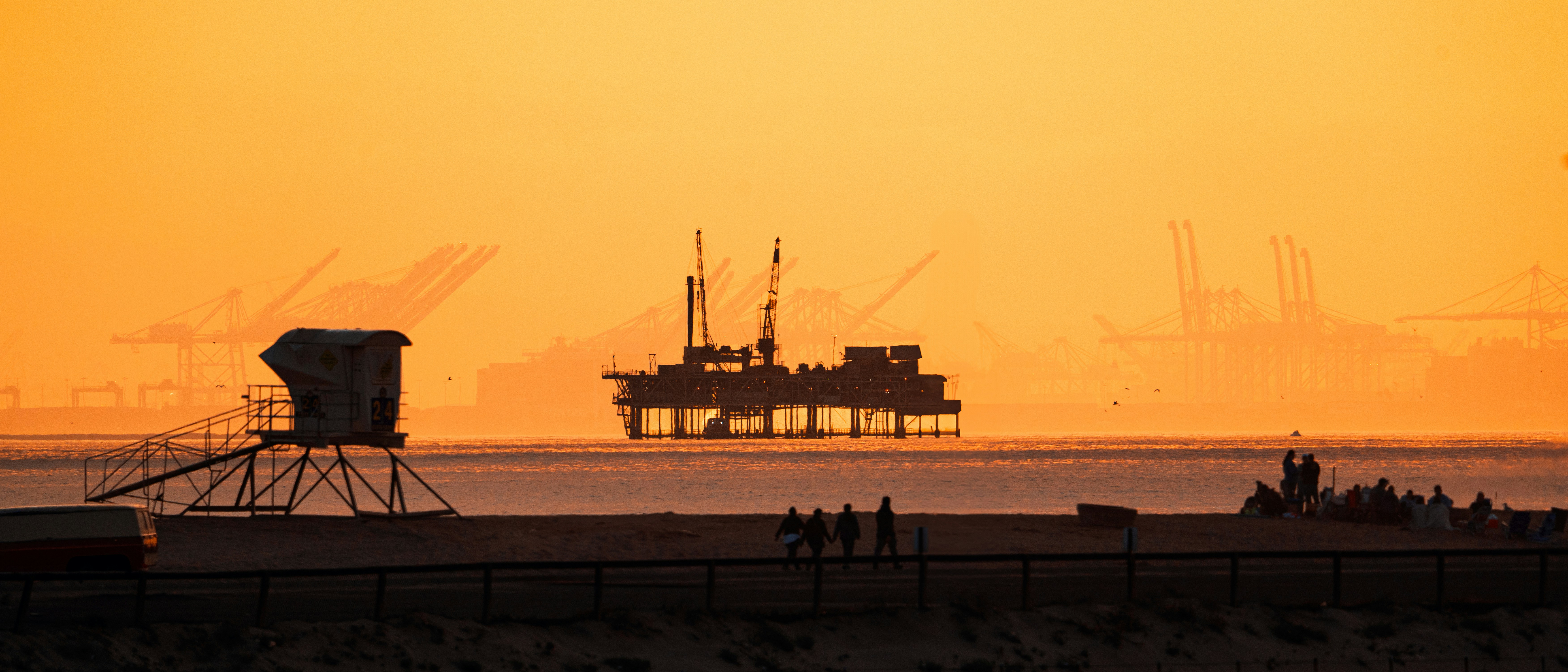 Silhouette at Sunset: Offshore Structures and Distant Cranes