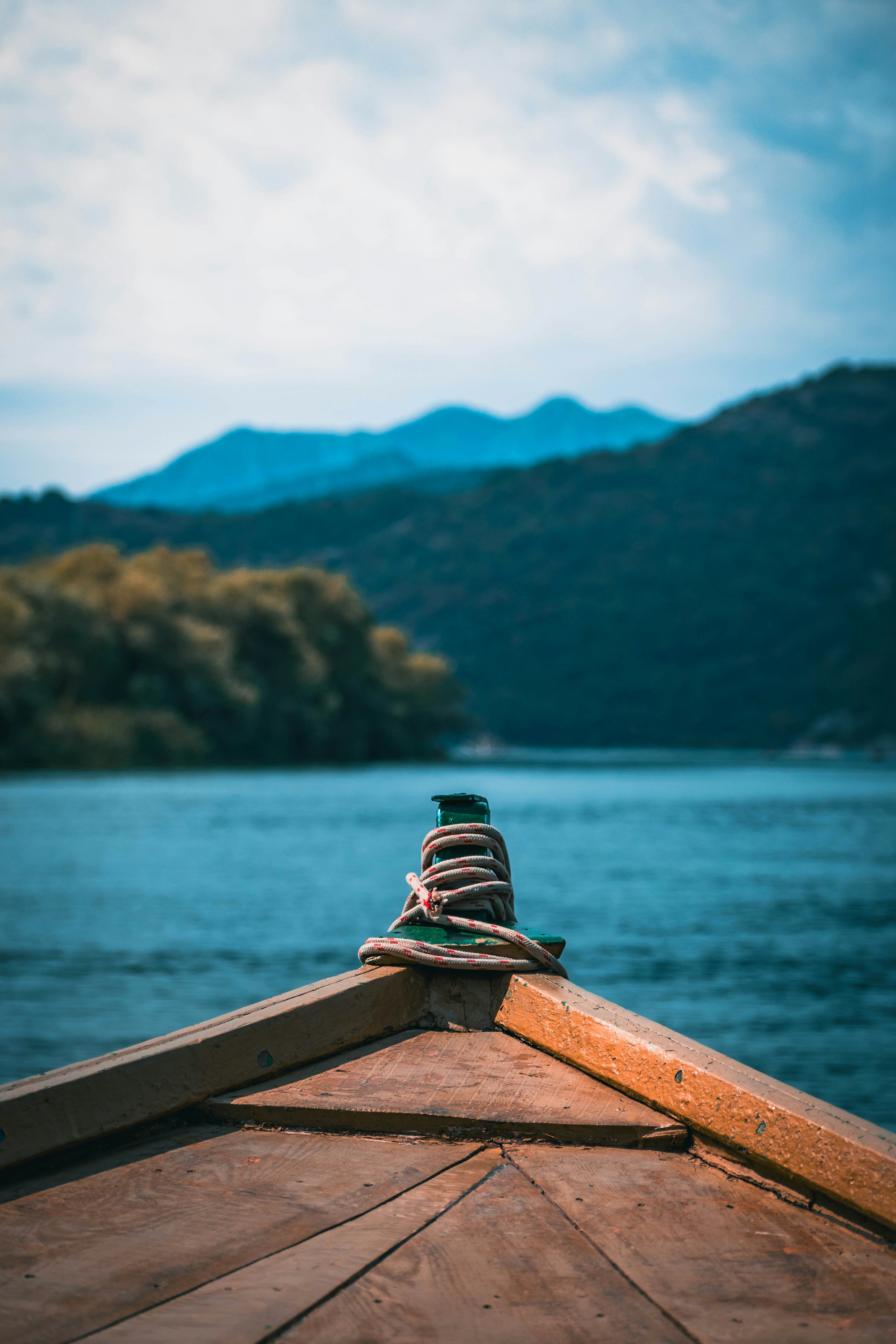 Bow of a Wooden Boat Pointing Toward a Serene Lake and Receding Hills