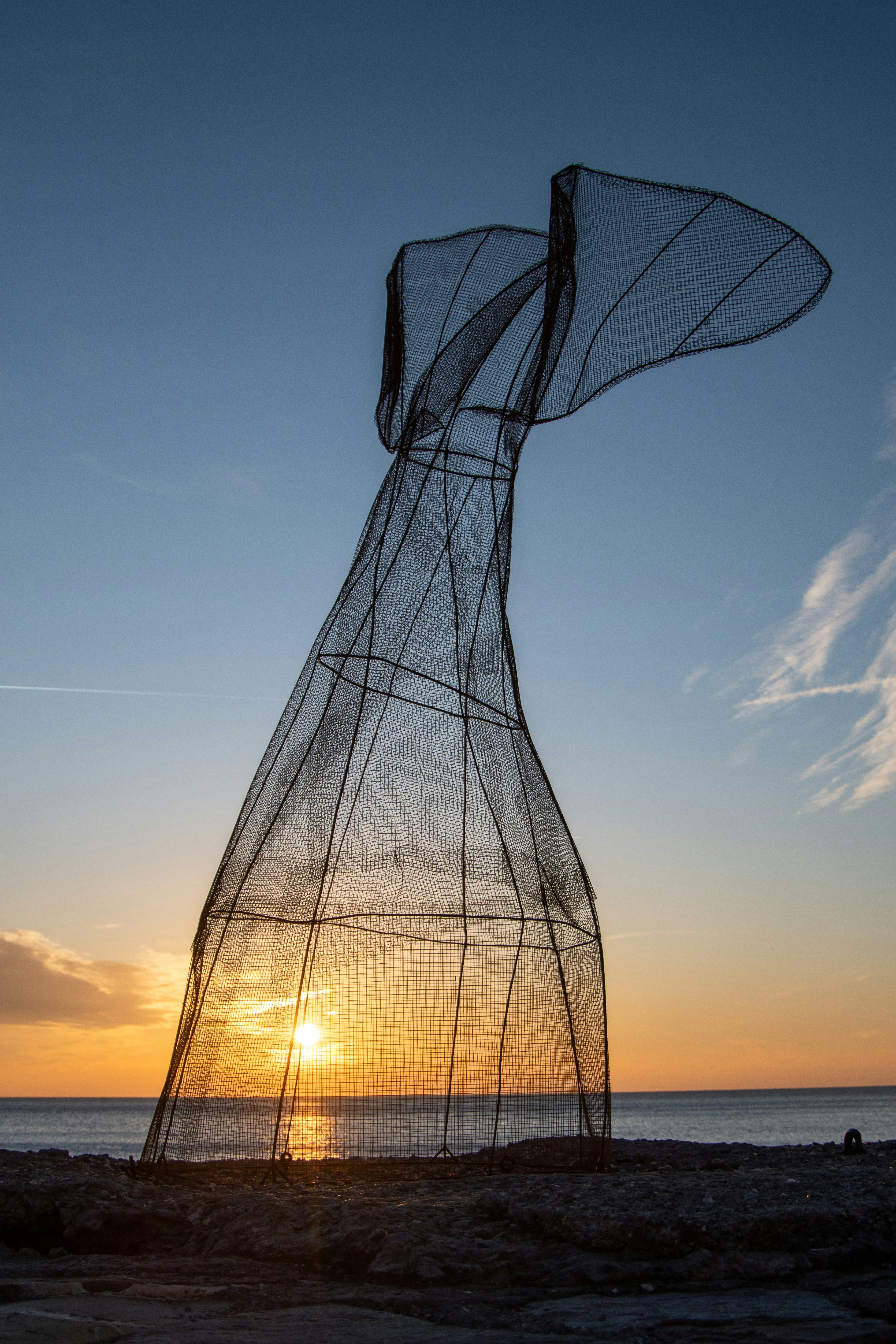 Silhouette of a coastal net sculpture at sunset
