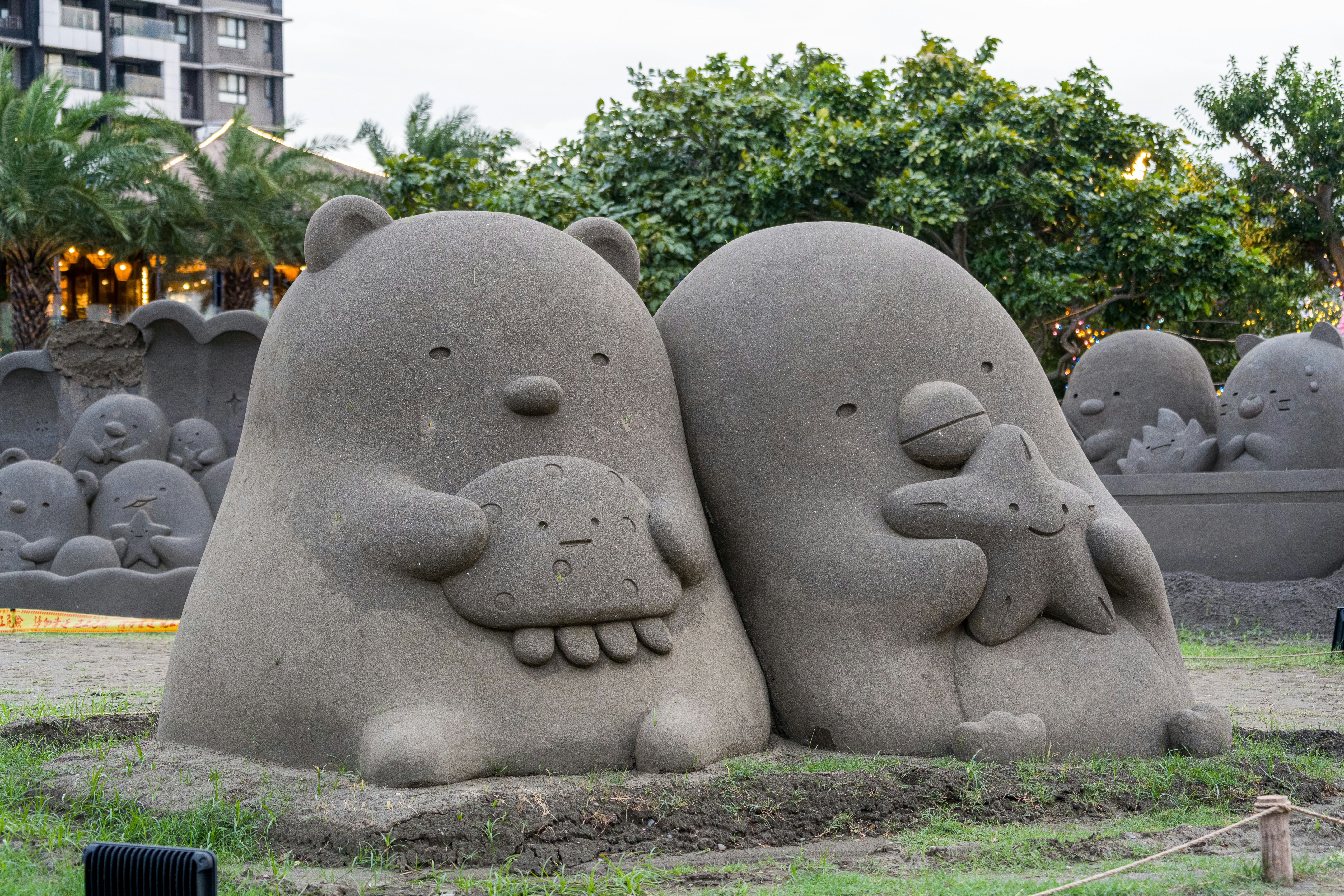 Two Smiling Sand Guardians with a Child Bot: A Playful Carved Scene