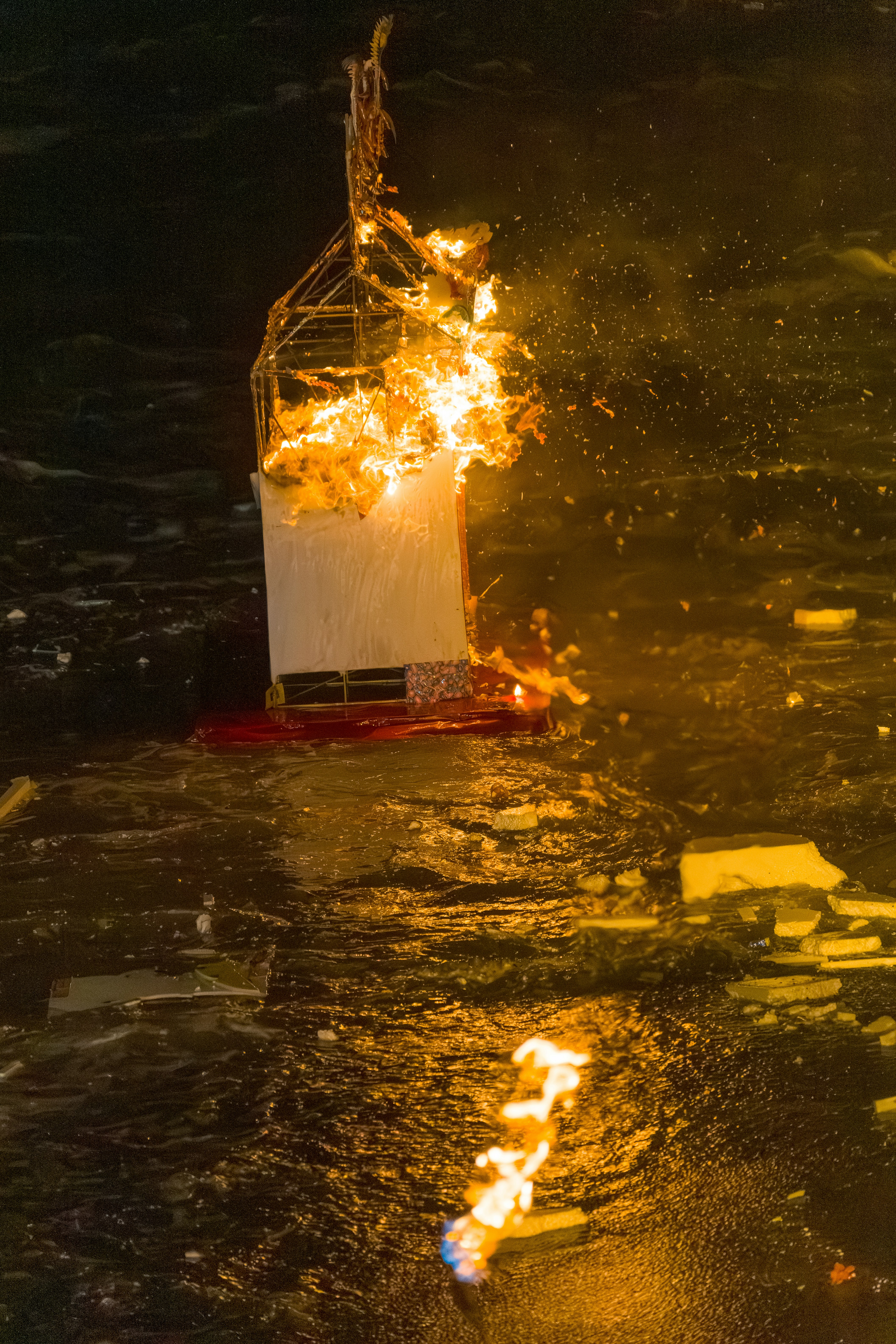 Flames Rise from a Burning Cage in a Dark Water Scene