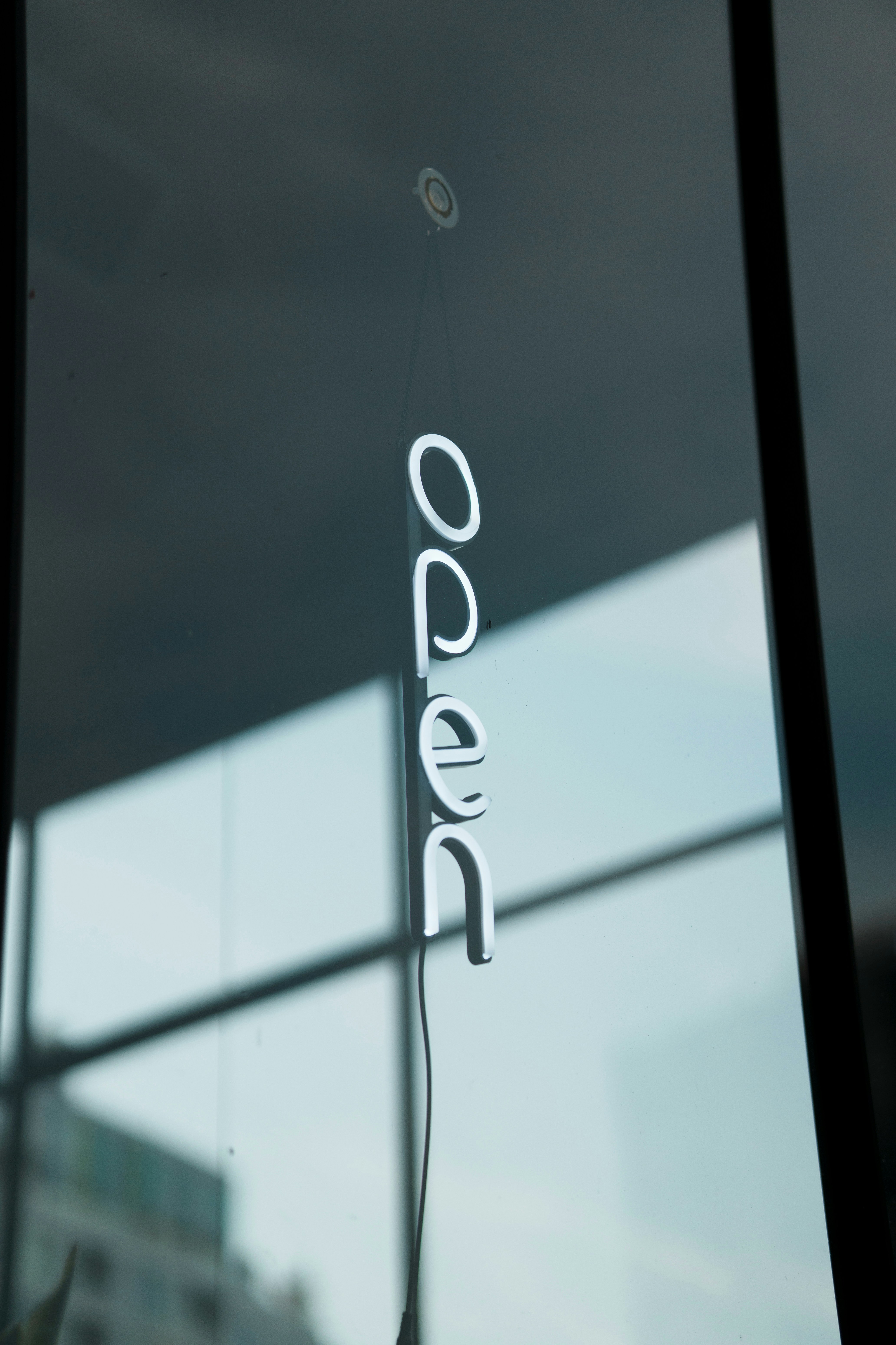 Neon Script Reflected: The Vertical Sign in a Glass Facade