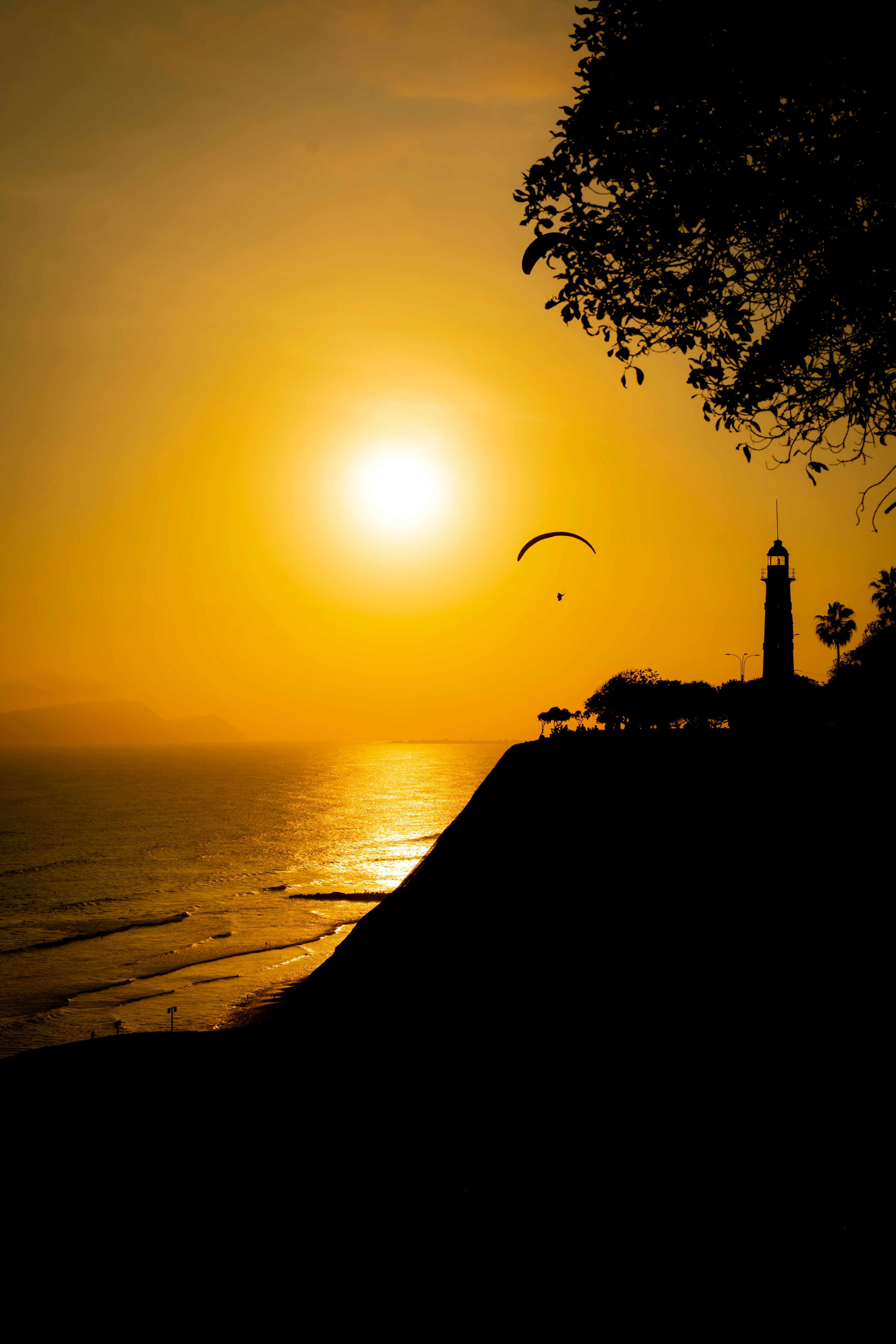 Sunlit Cliffside with Parachute Kite Over the Sea