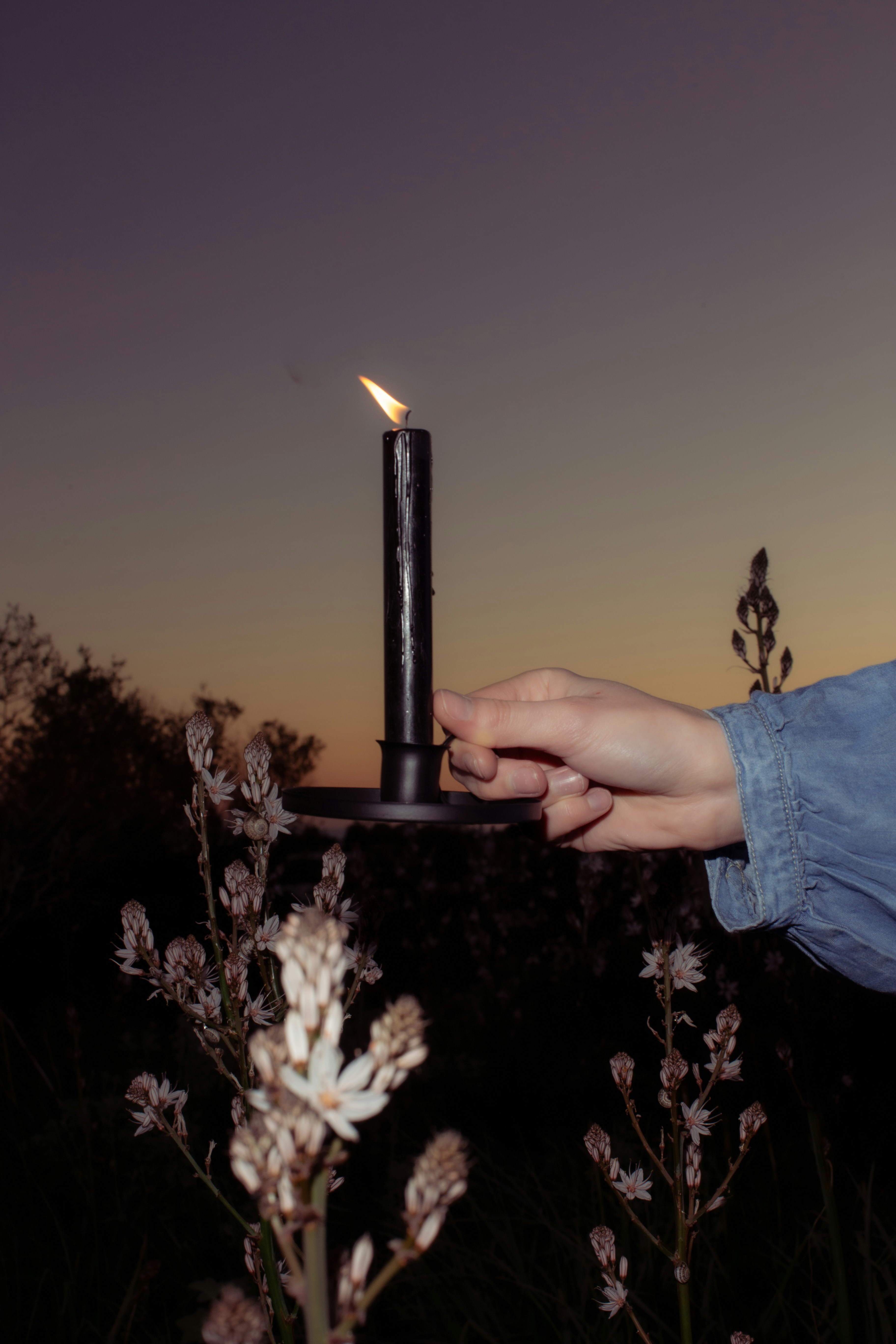 Evening Flame: A Hand Steadying a Lone Candle at Dusk