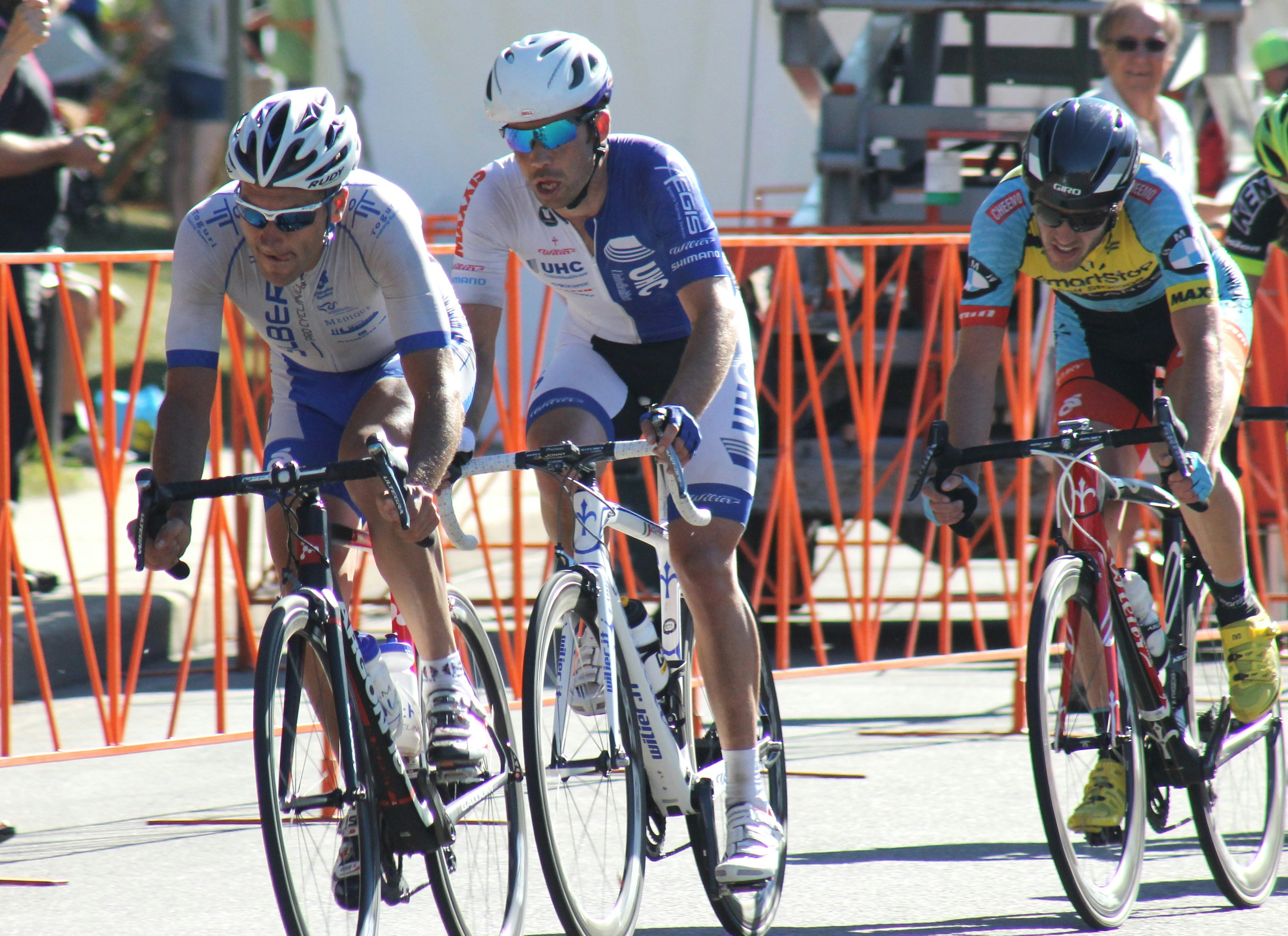 Three Cyclists Lean into the Final Sprint on a Sunlit Circuit