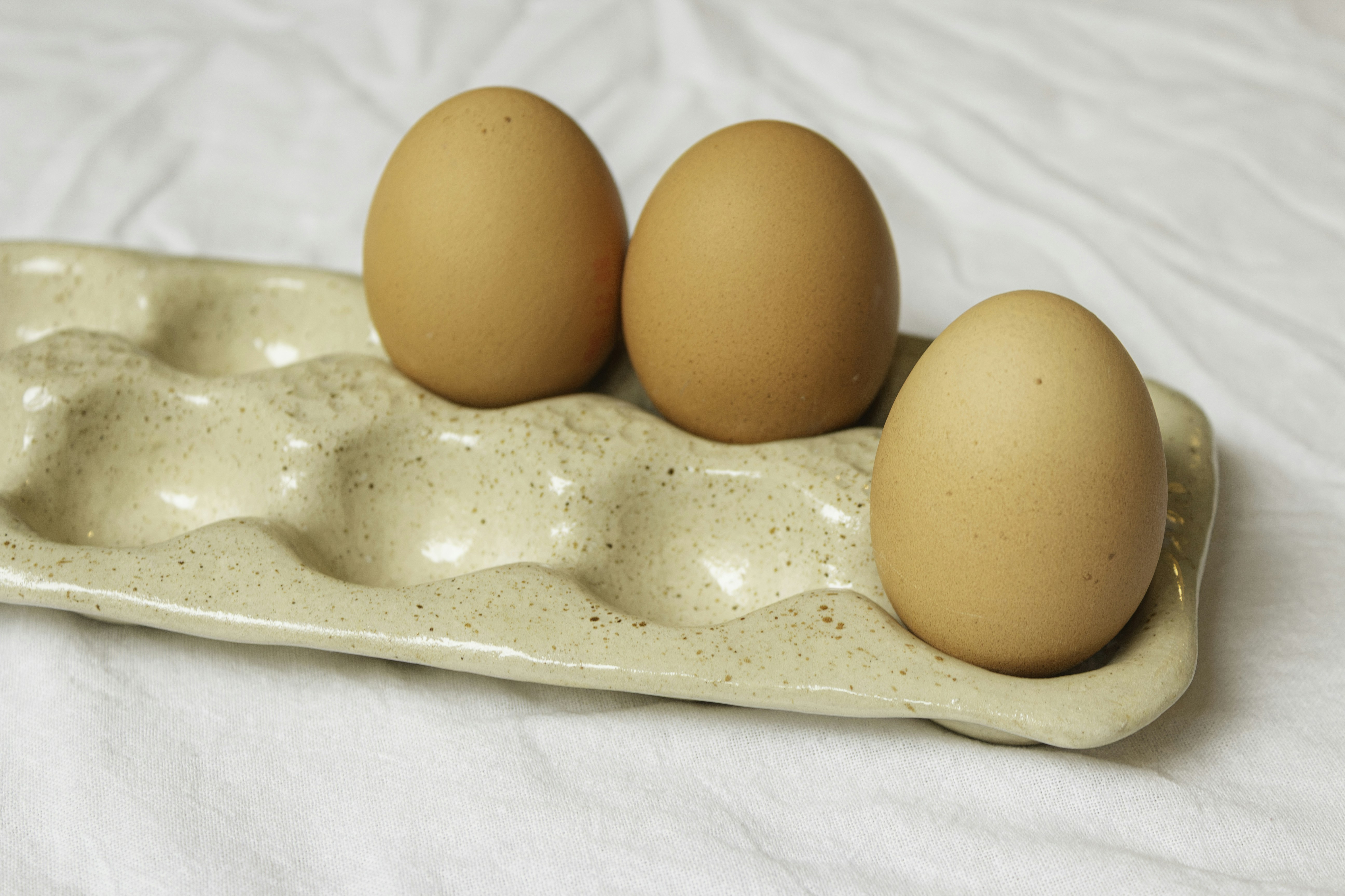 Three Eggs in a Sloped Egg Tray on Soft Linen