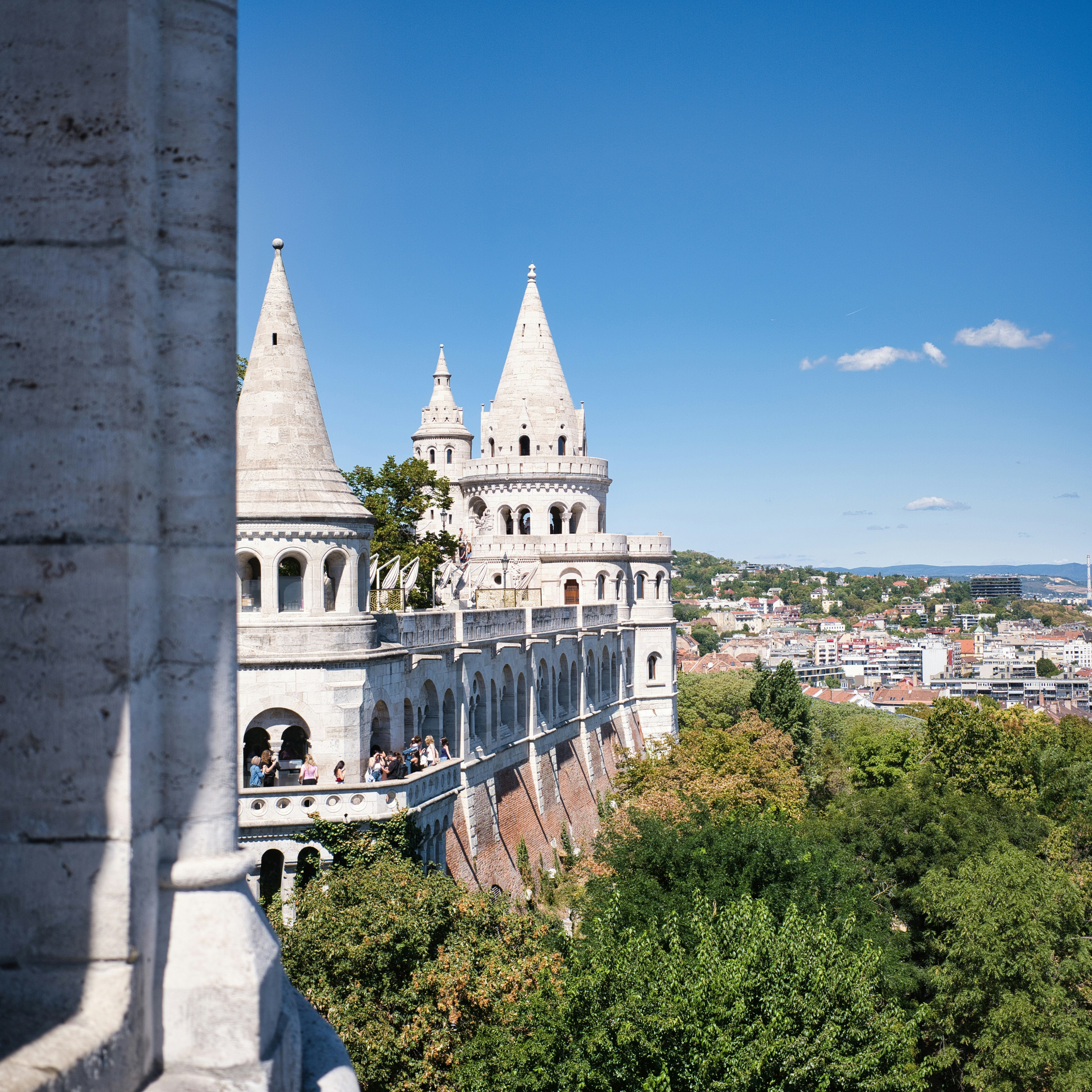 Castle of stone towers over a hillside city beneath a clear blue sky