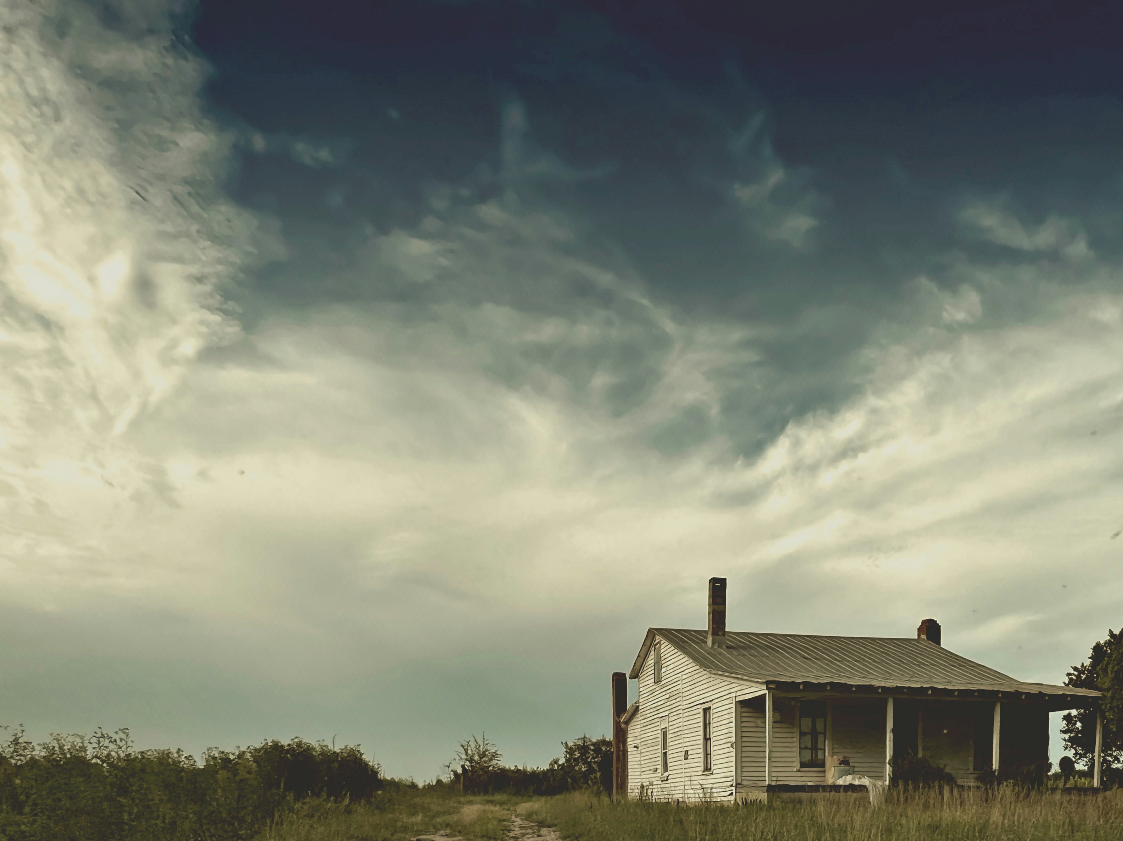 Deserted farmhouse under a sweeping, moody sky