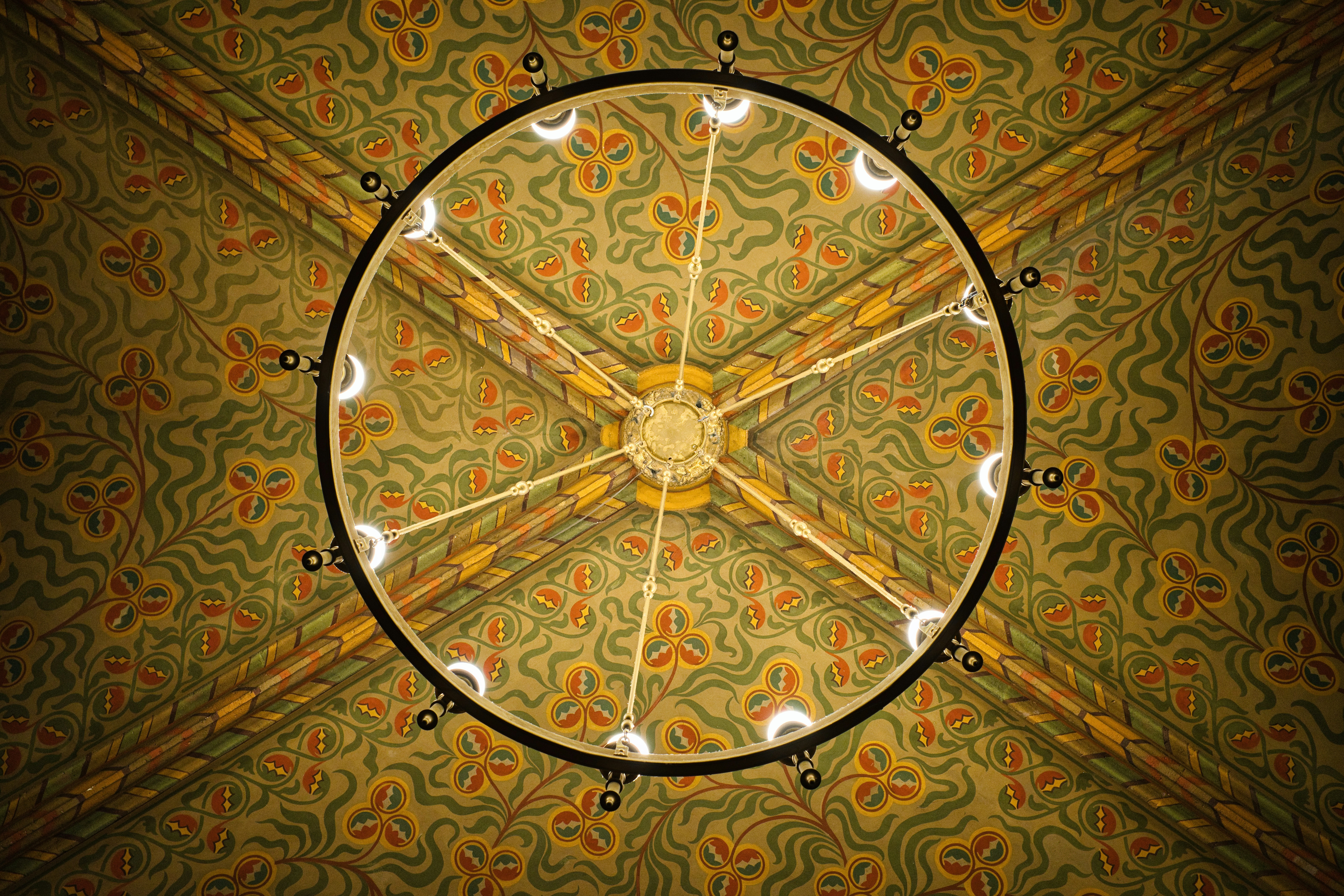 Circular chandelier rosette: symmetry and ornate ceiling in a sunlit dome