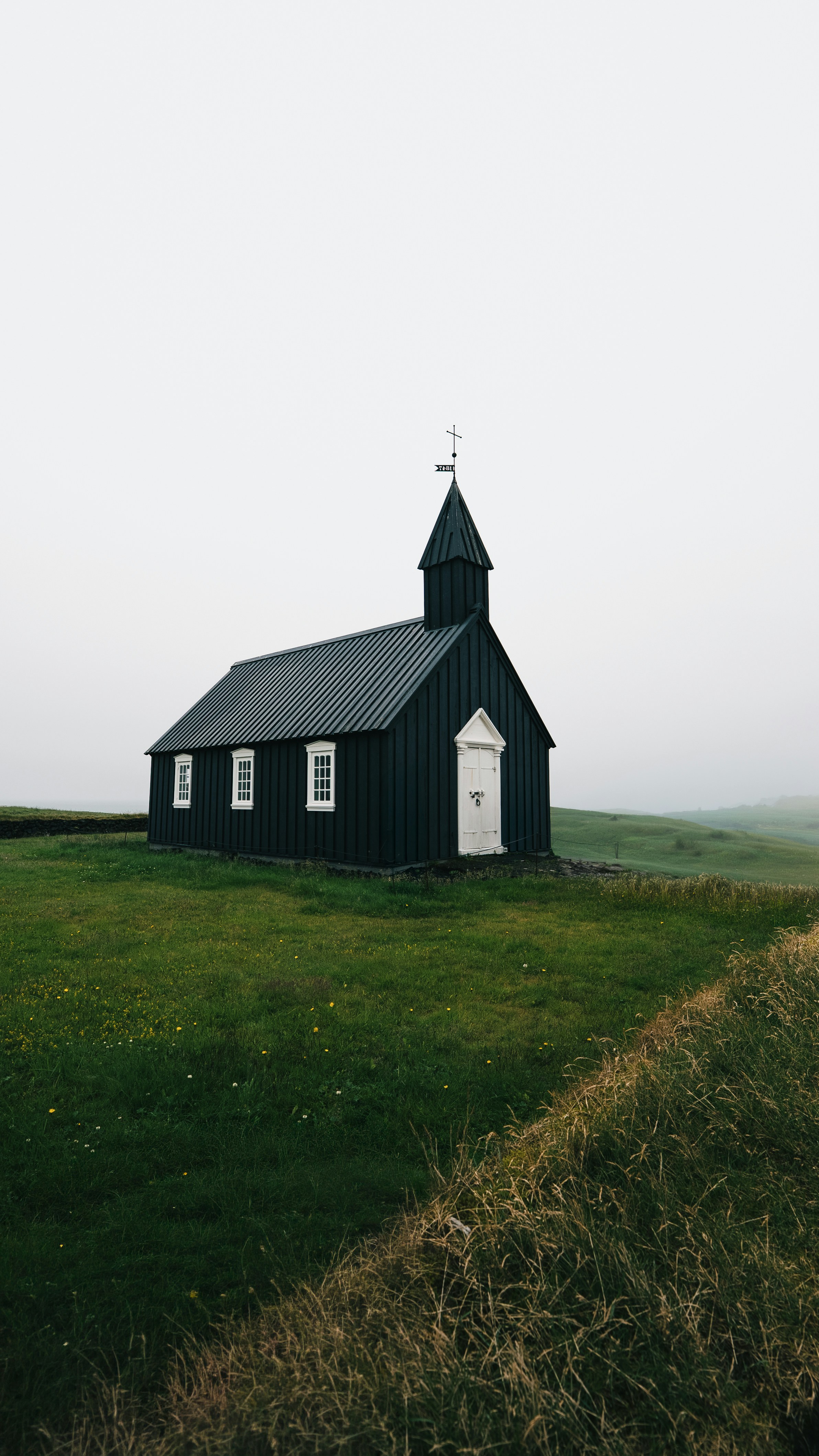 Solitary chapel on a windswept hill under pale skies