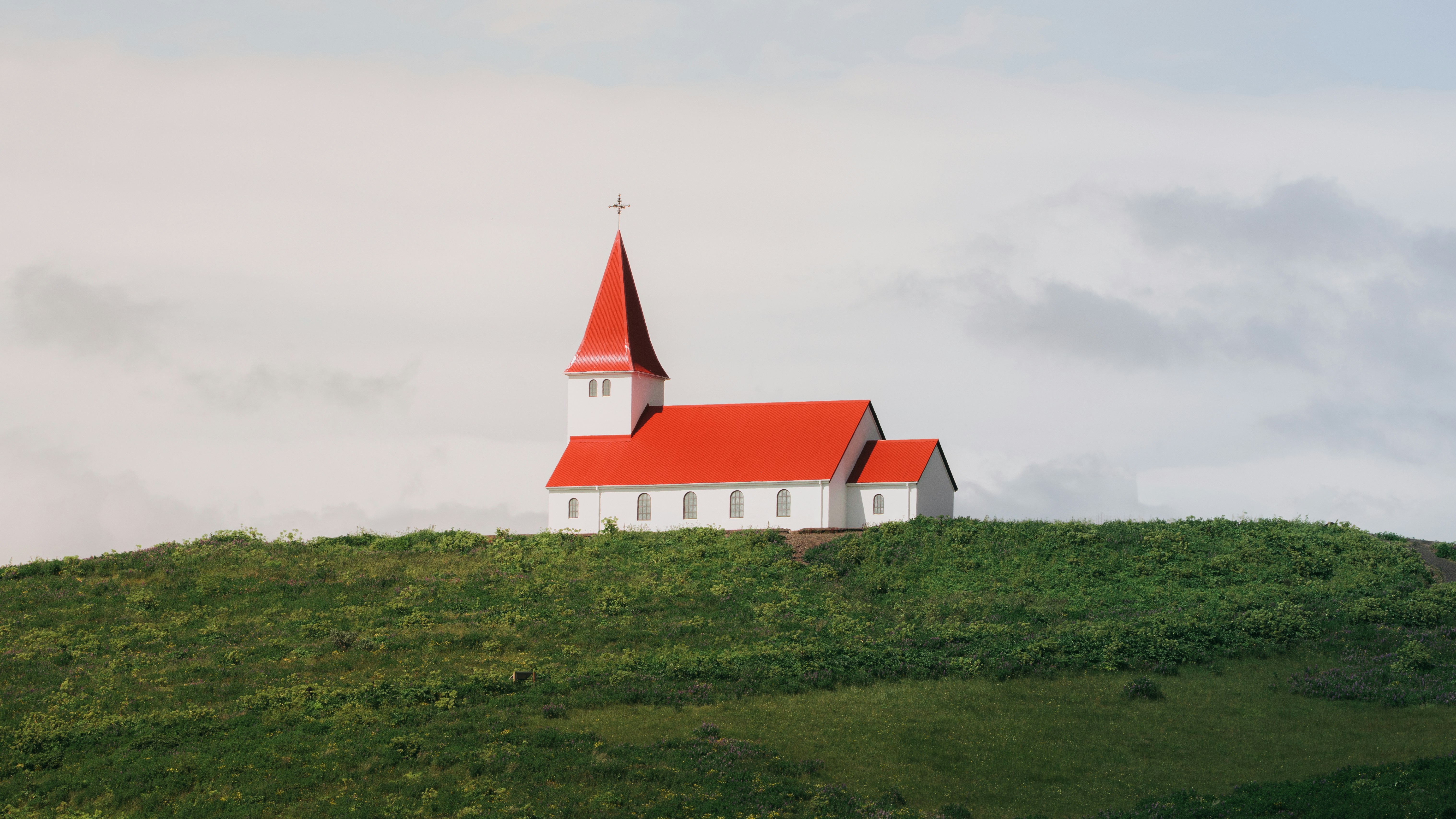 Red-roofed church perched on a grassy hill